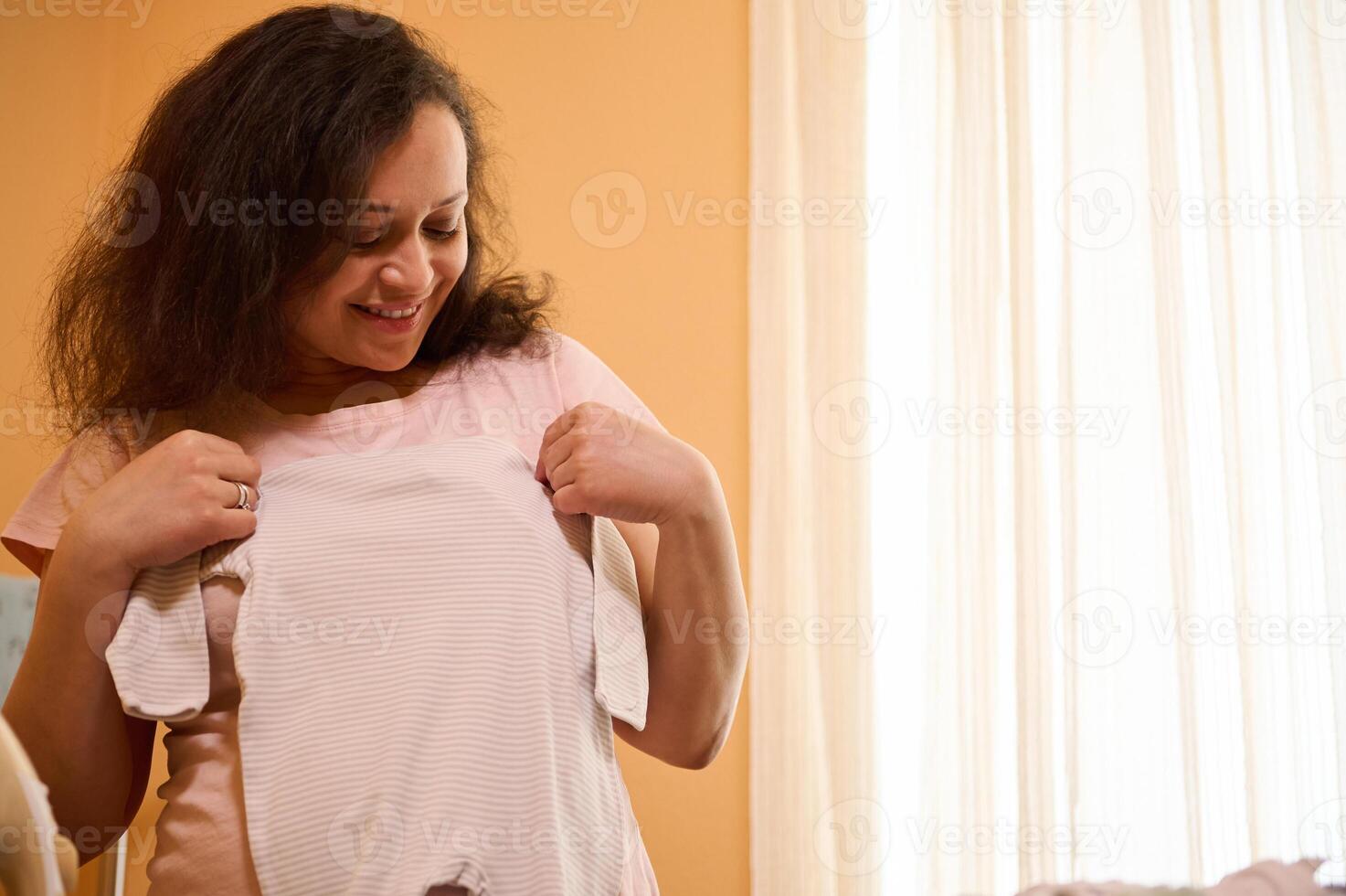 Smiling Expectant Mother Pregnant Woman Holds Ironed Newborn Clothes Expressing Positive
