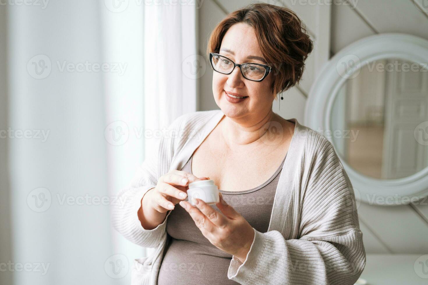 Smiling middle aged plus size woman with day cream near window at home 23740949 Stock Photo at ...