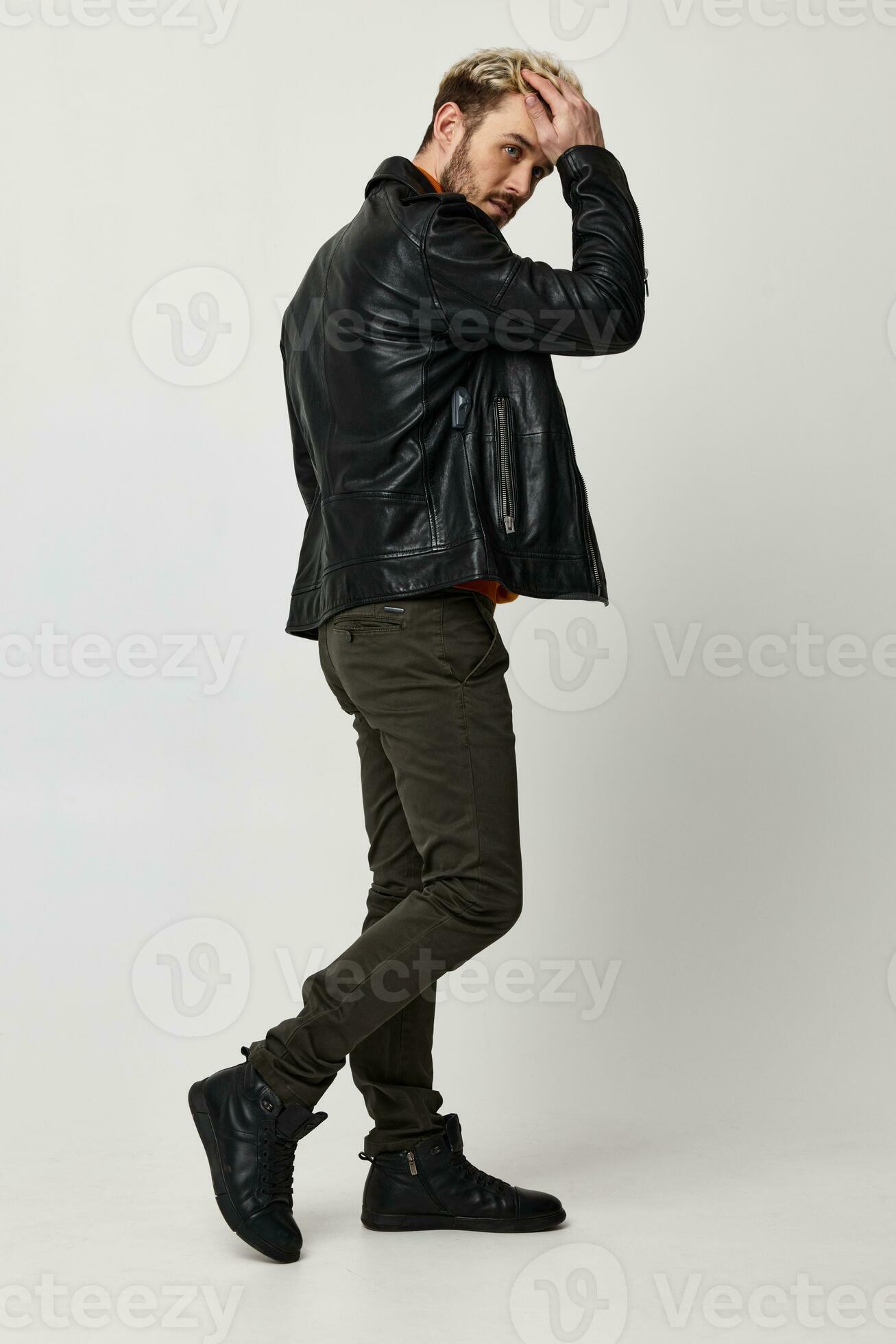 elegant man in a leather jacket touches his head with his hand on a ...