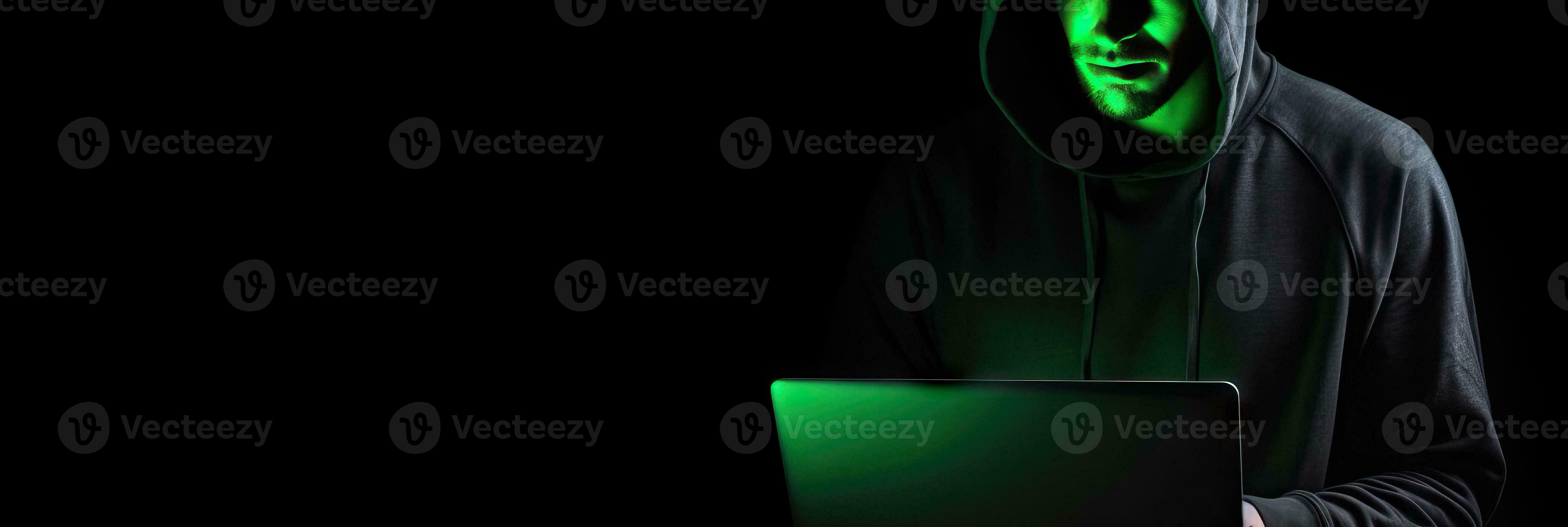 Hacker without face in a hood holds a laptop. on a dark background. Banner for cyber security ...