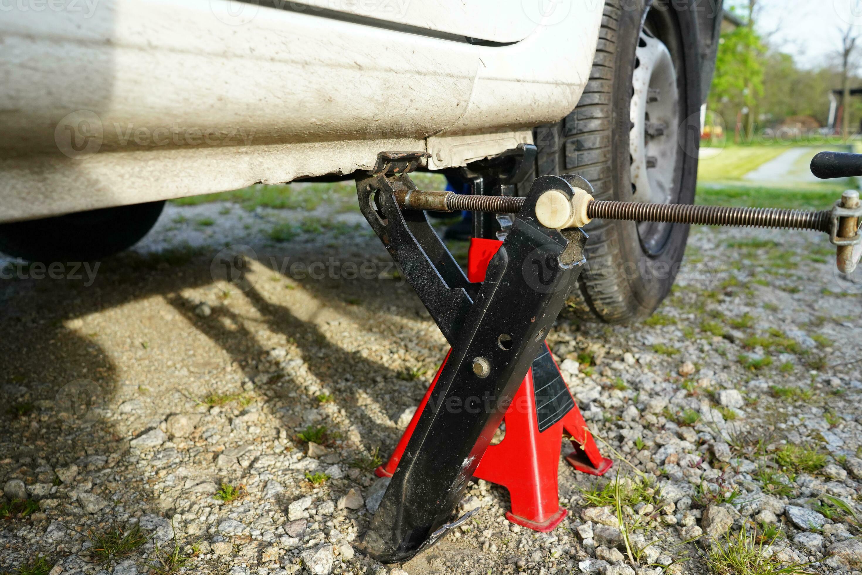 Car lifted on jack. Mechanic lifting up the car with car jack. Tire change. Mechanic changing ...