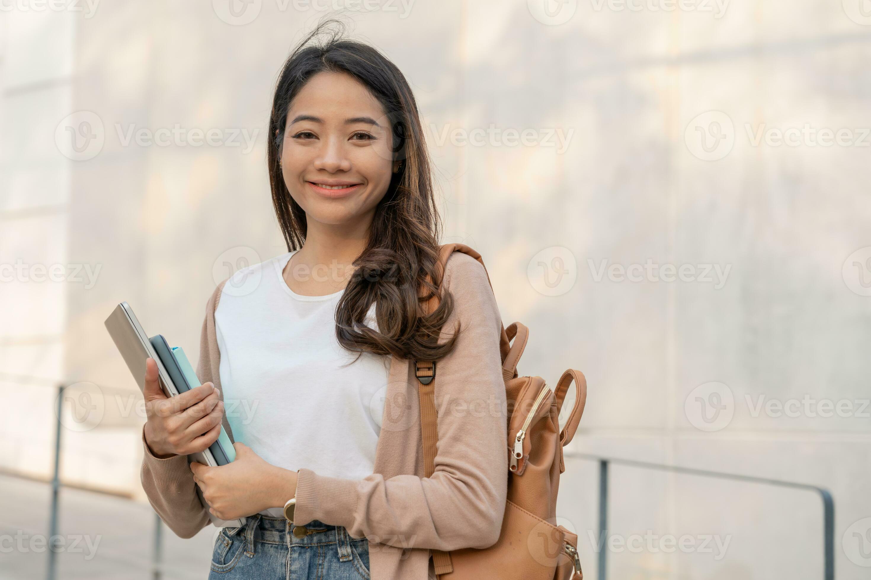Beautiful student asian woman with backpack and books outdoor. Smile girl happy carrying a lot ...