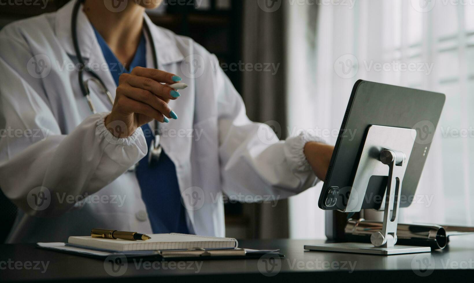 grave hembra médico utilizando ordenador portátil y escritura notas en médico diario sentado a ...