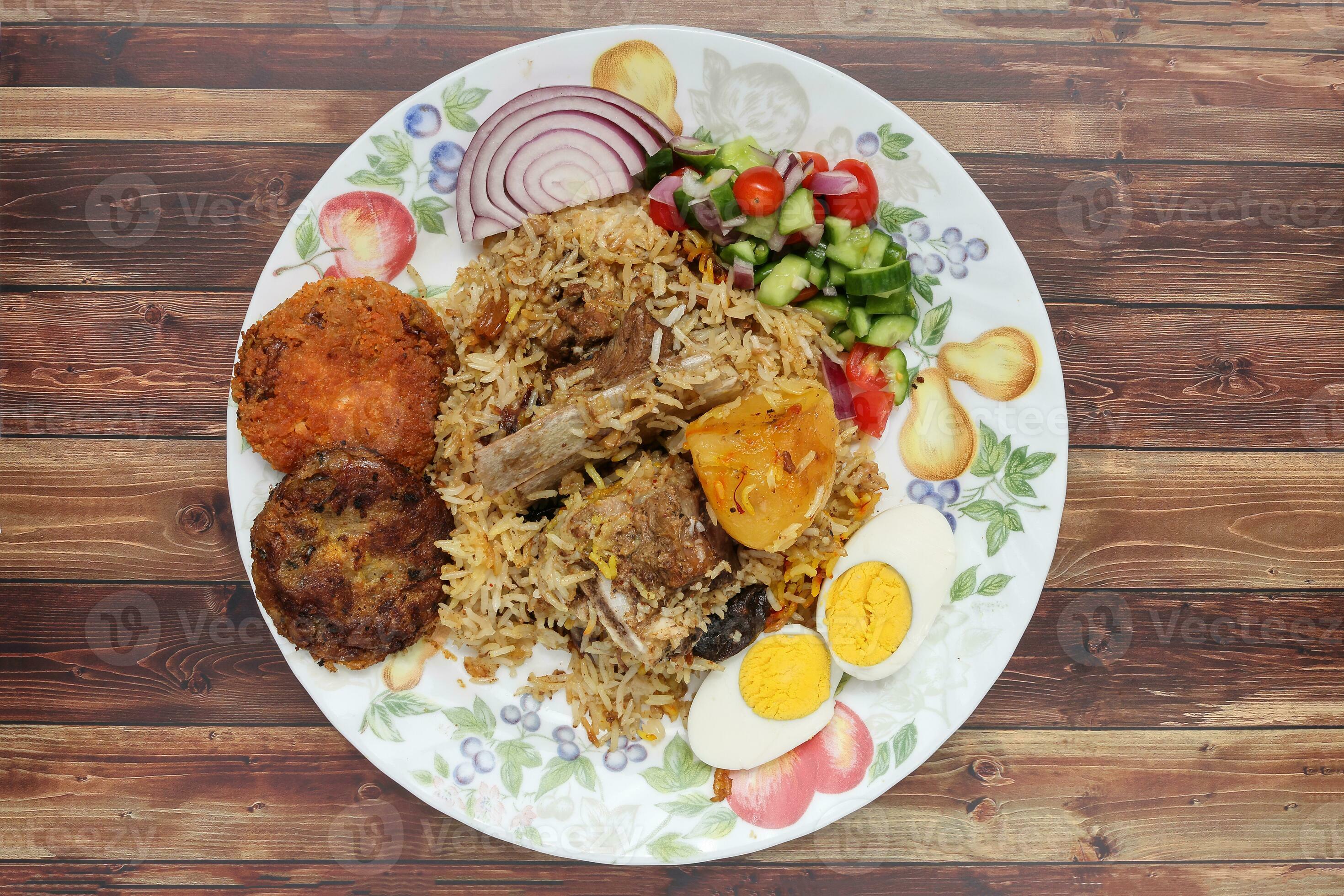 Home style mutton kacchi biryani with potato chop tomato cucumber onion ...