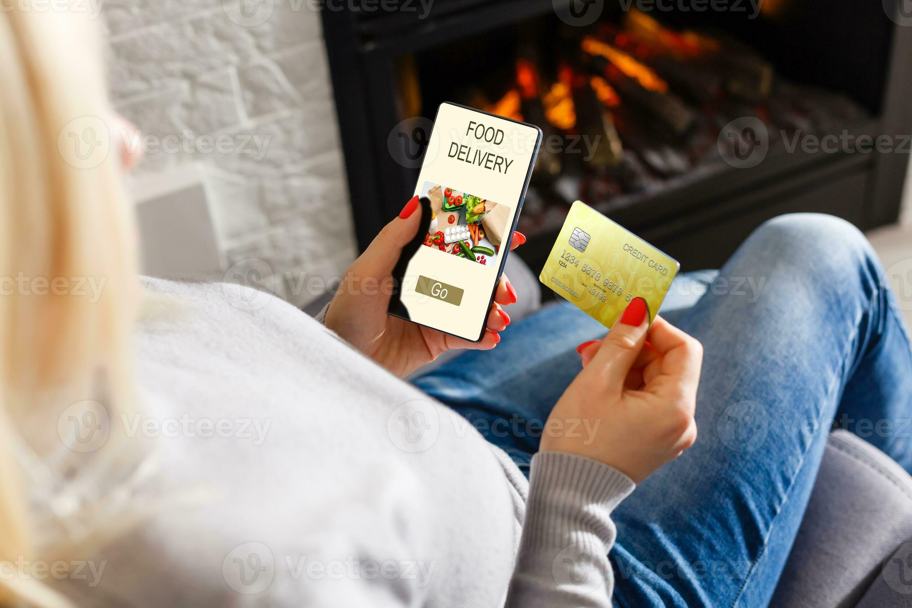 Girl ordering pizza online on smartphone, with table and coffee and plant in background 24497100 ...