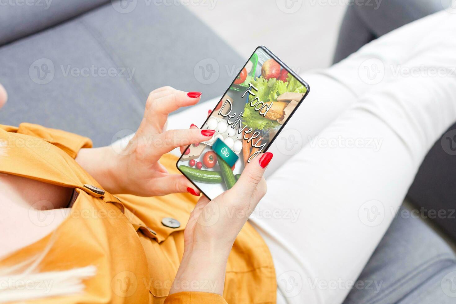 Girl ordering pizza online on smartphone, with table and coffee and plant in background 24497130 ...