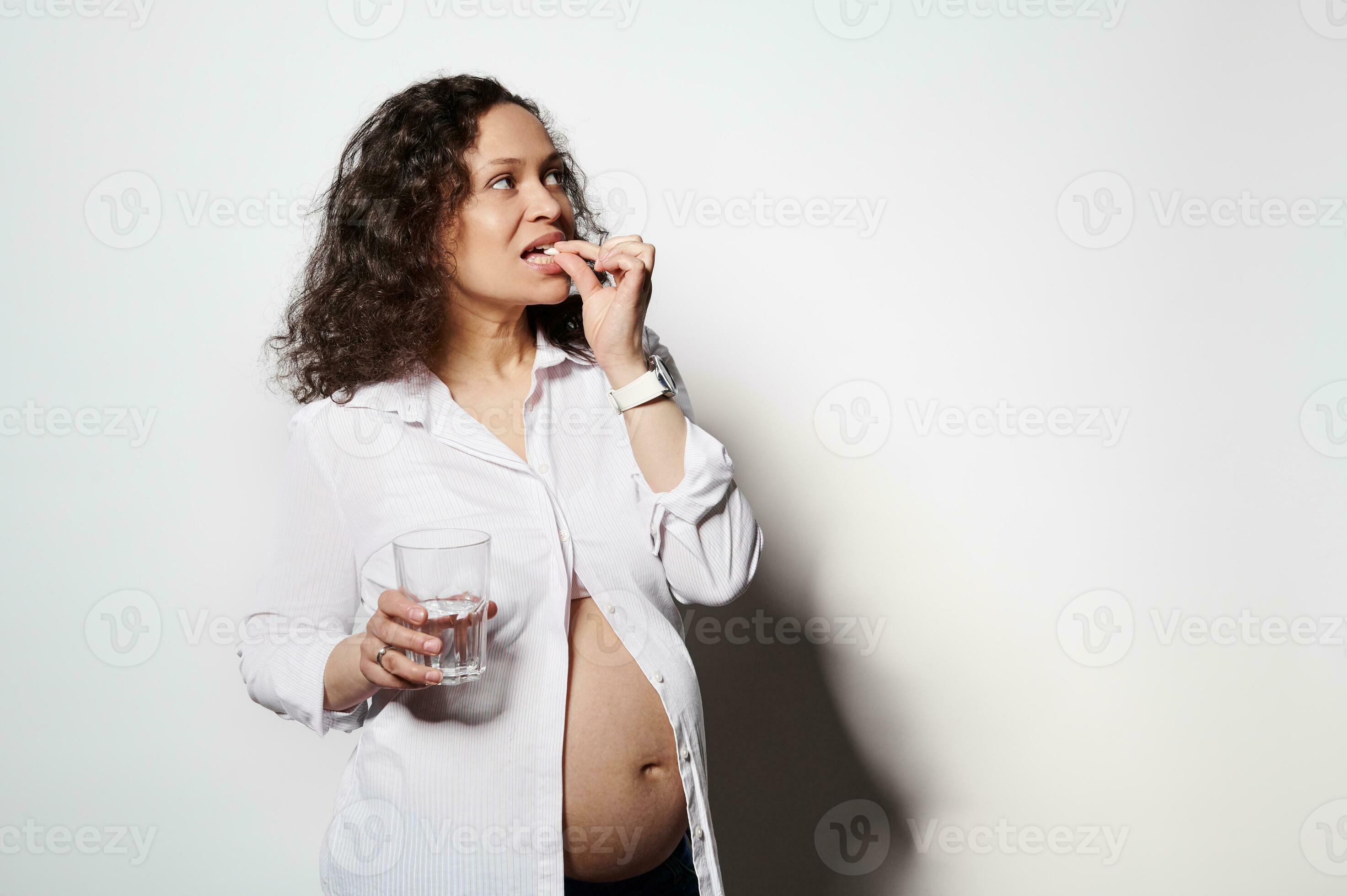 Multi Ethnic Adult Pregnant Woman Holding Glass Of Water And Pill