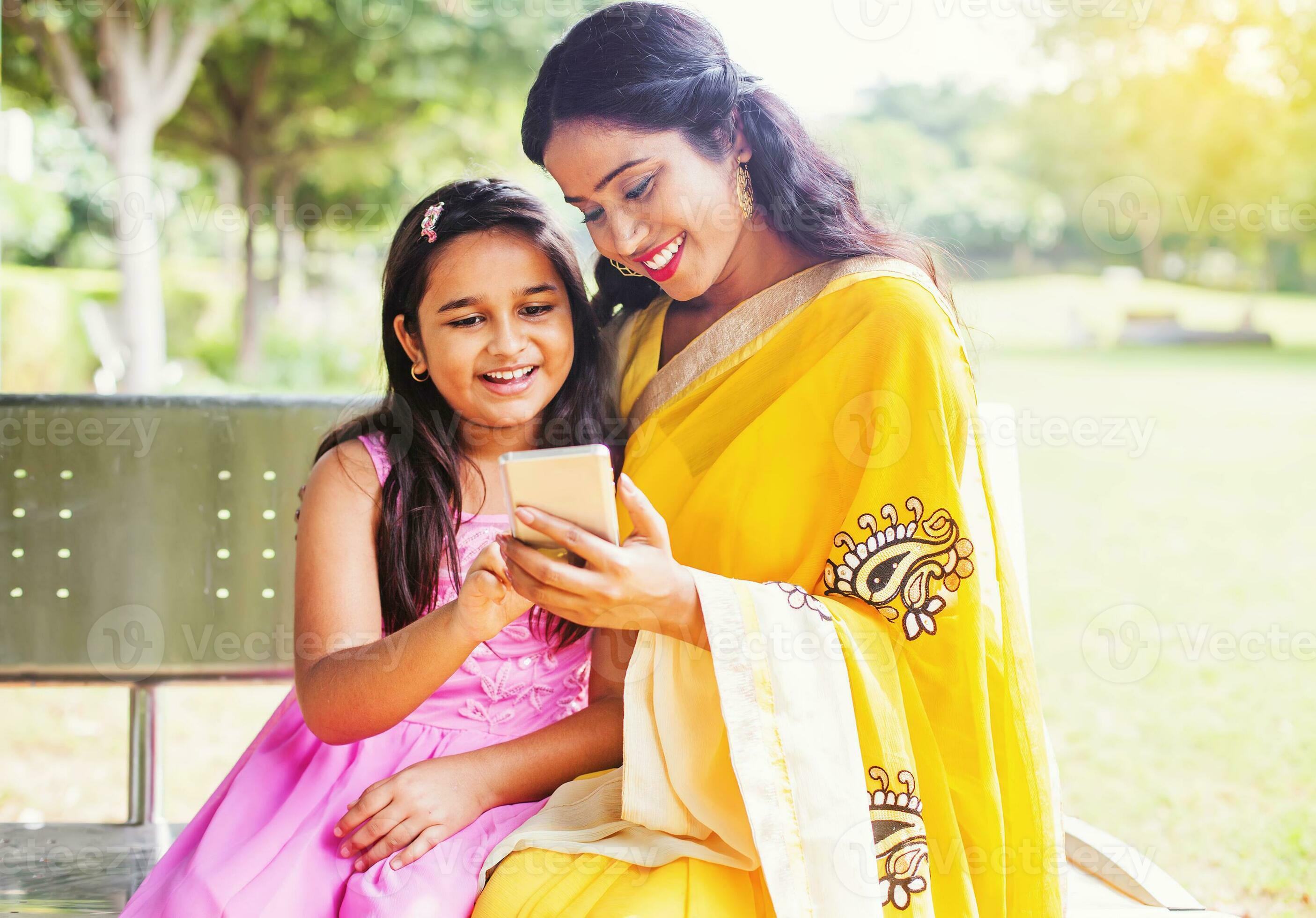 Indian Mother And Daughter In Traditional Ethnic Clothes Using Mobile