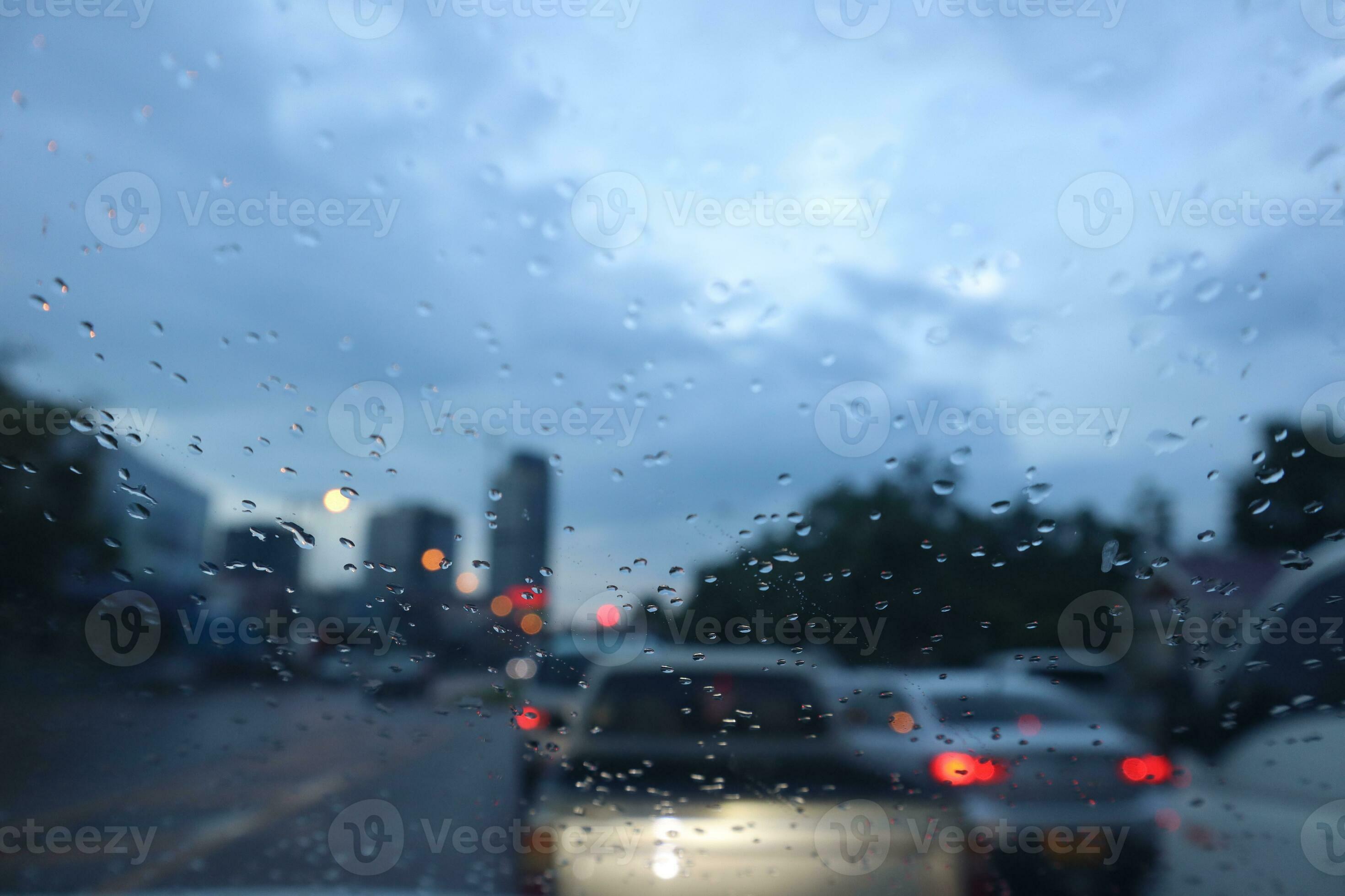 Blurred view of car on road through wet windshield with rain drops ...