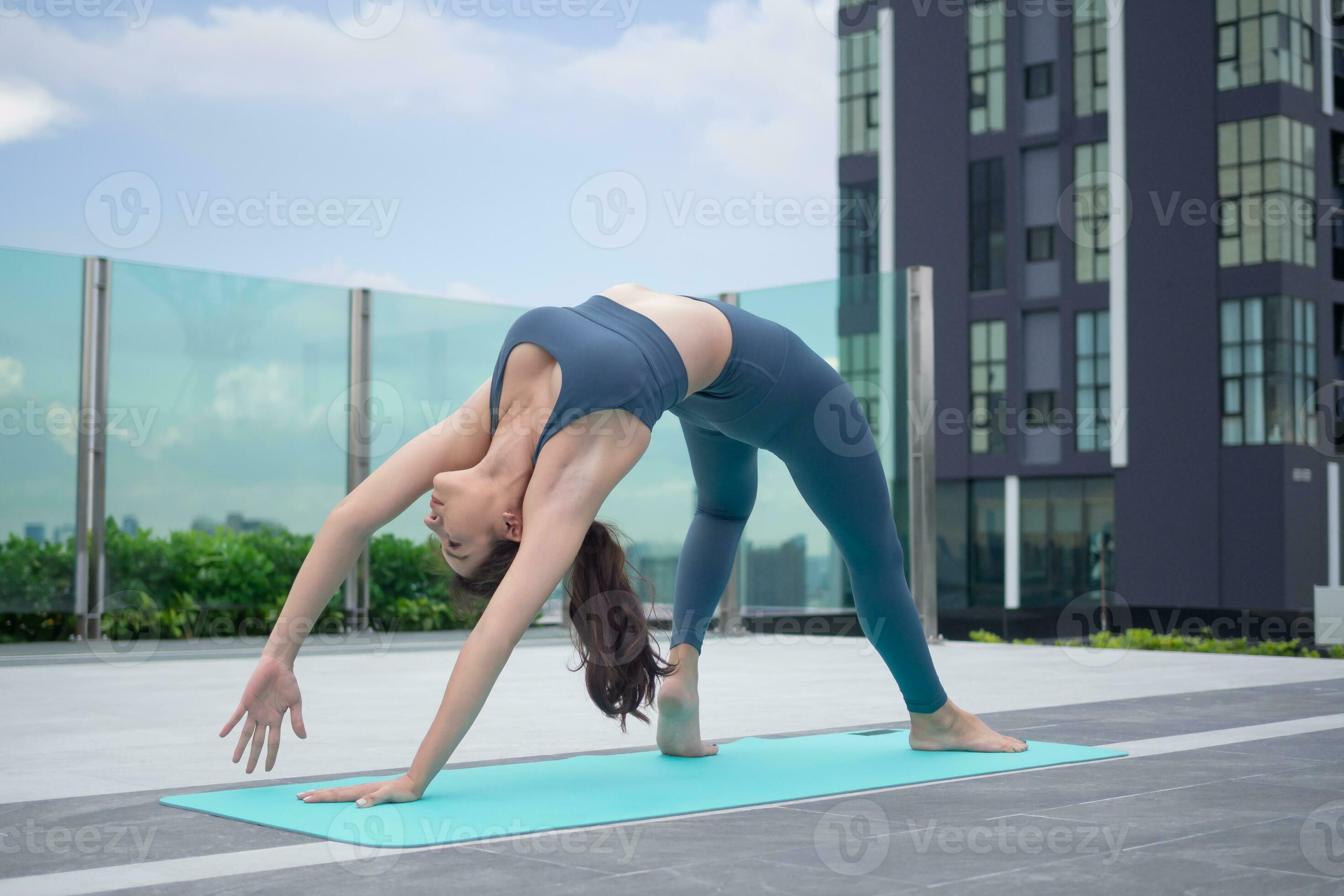 Slim woman practicing yoga on the balcony of her condo. Asian woman doing exercises in morning ...
