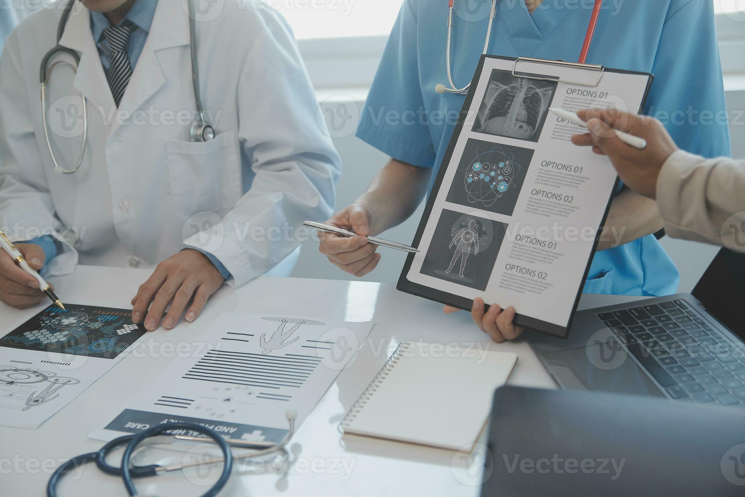 Multiracial team of doctors discussing a patient standing grouped in ...