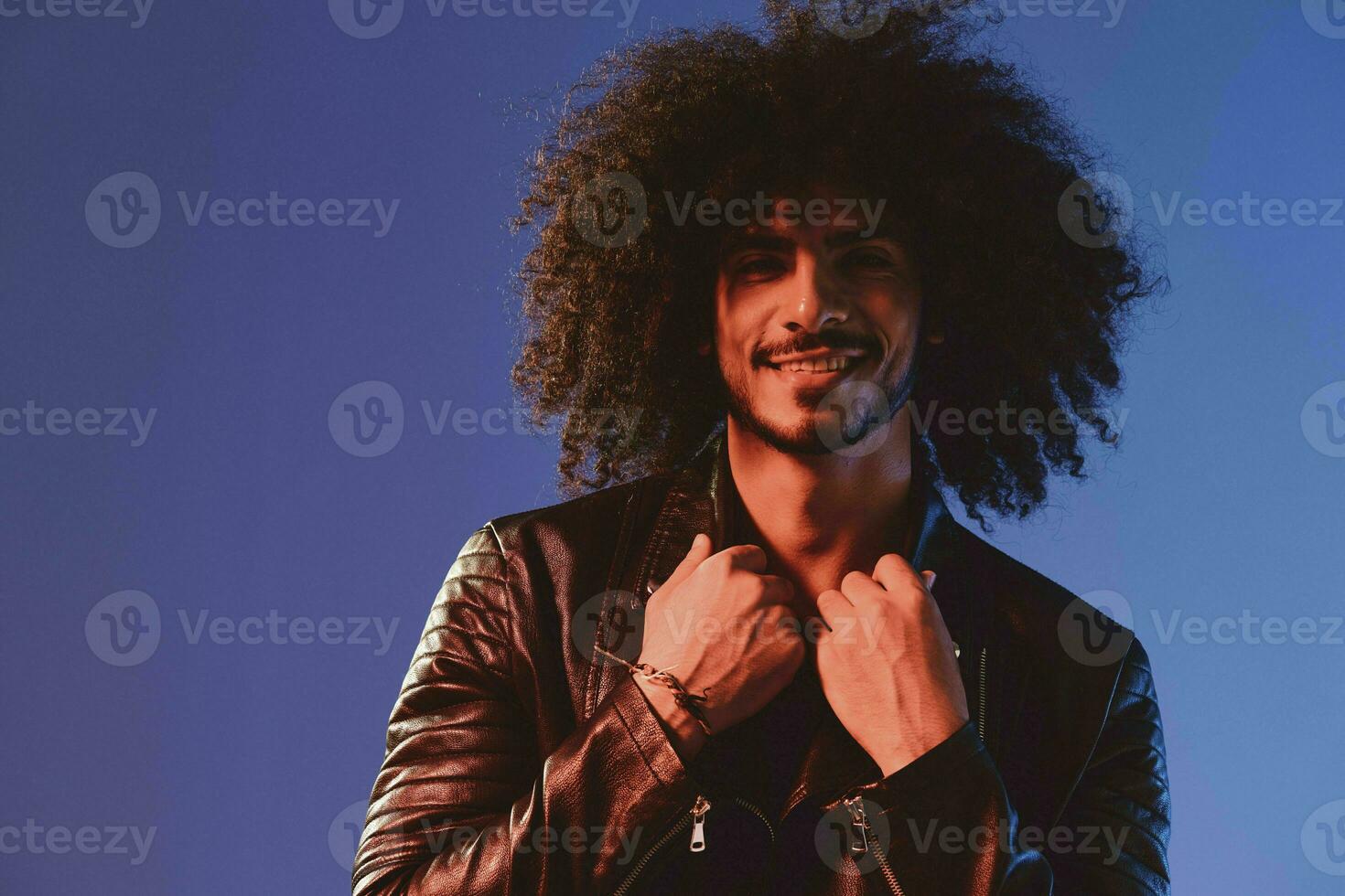 Portrait of a stylish man with curly hair with glasses smile on blue ...