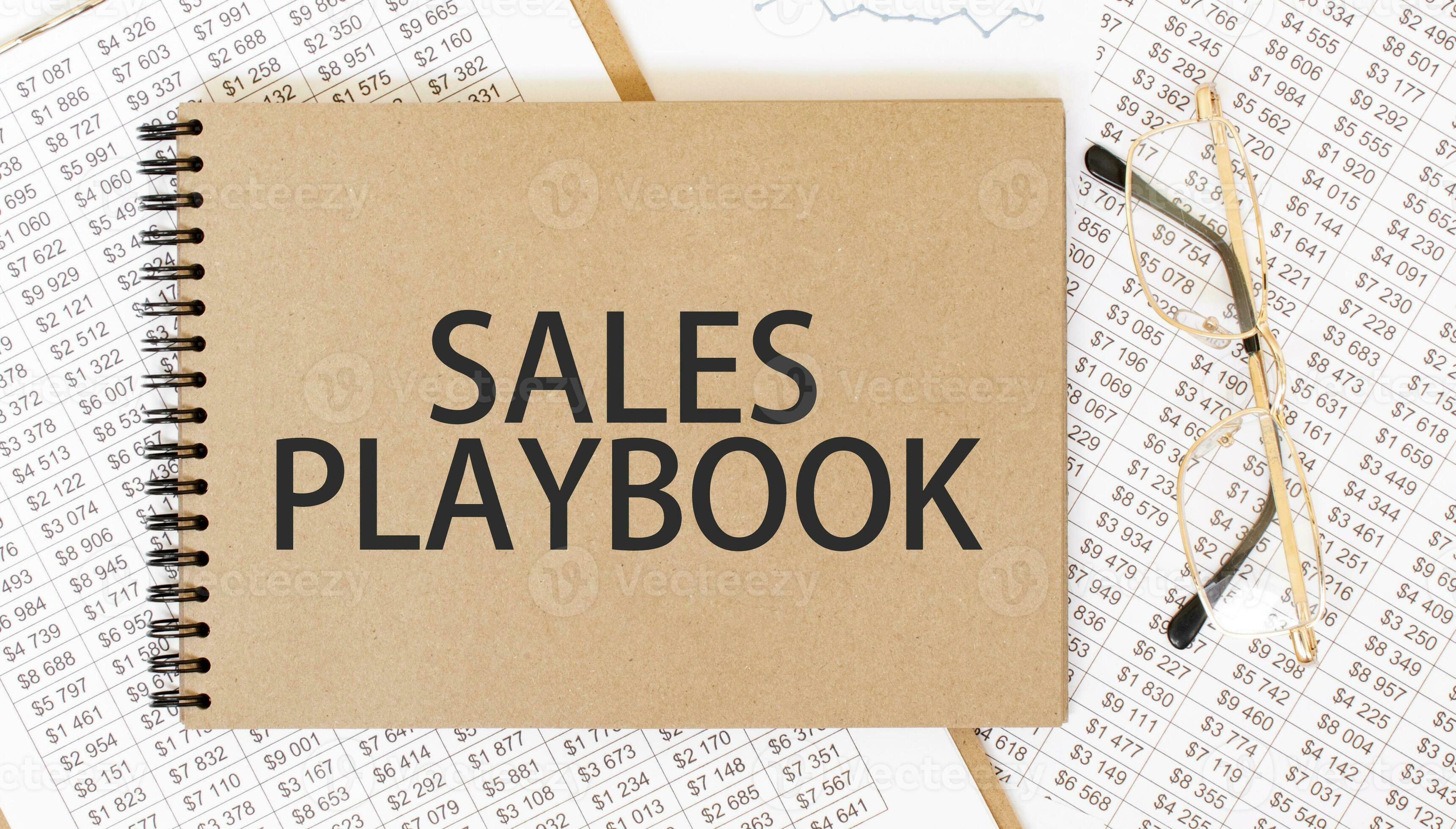 Craft colour notepad with text SALES PLAYBOOK. Notepad with eyeglasses and text documents ...