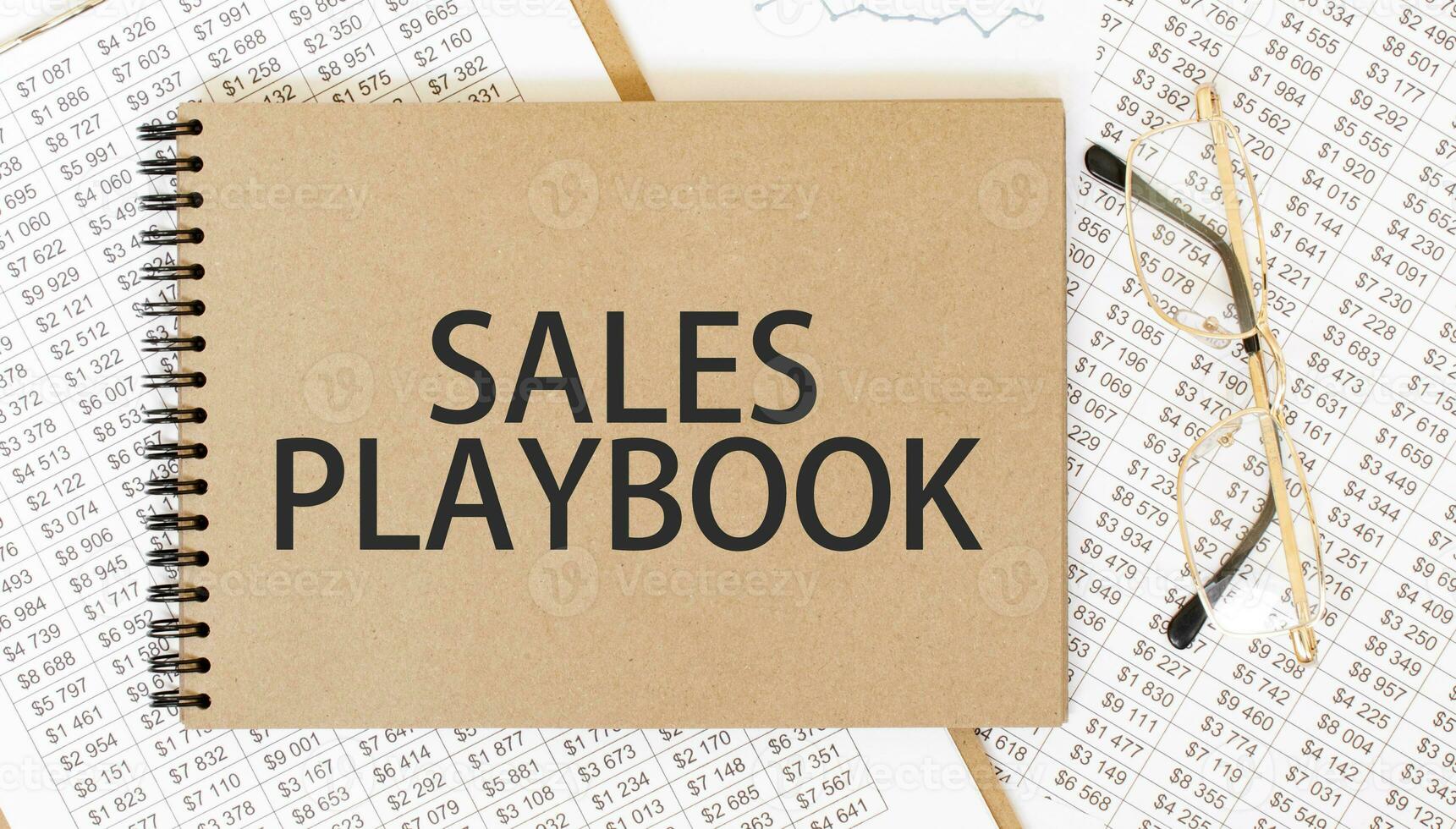 Craft colour notepad with text SALES PLAYBOOK. Notepad with eyeglasses and text documents ...