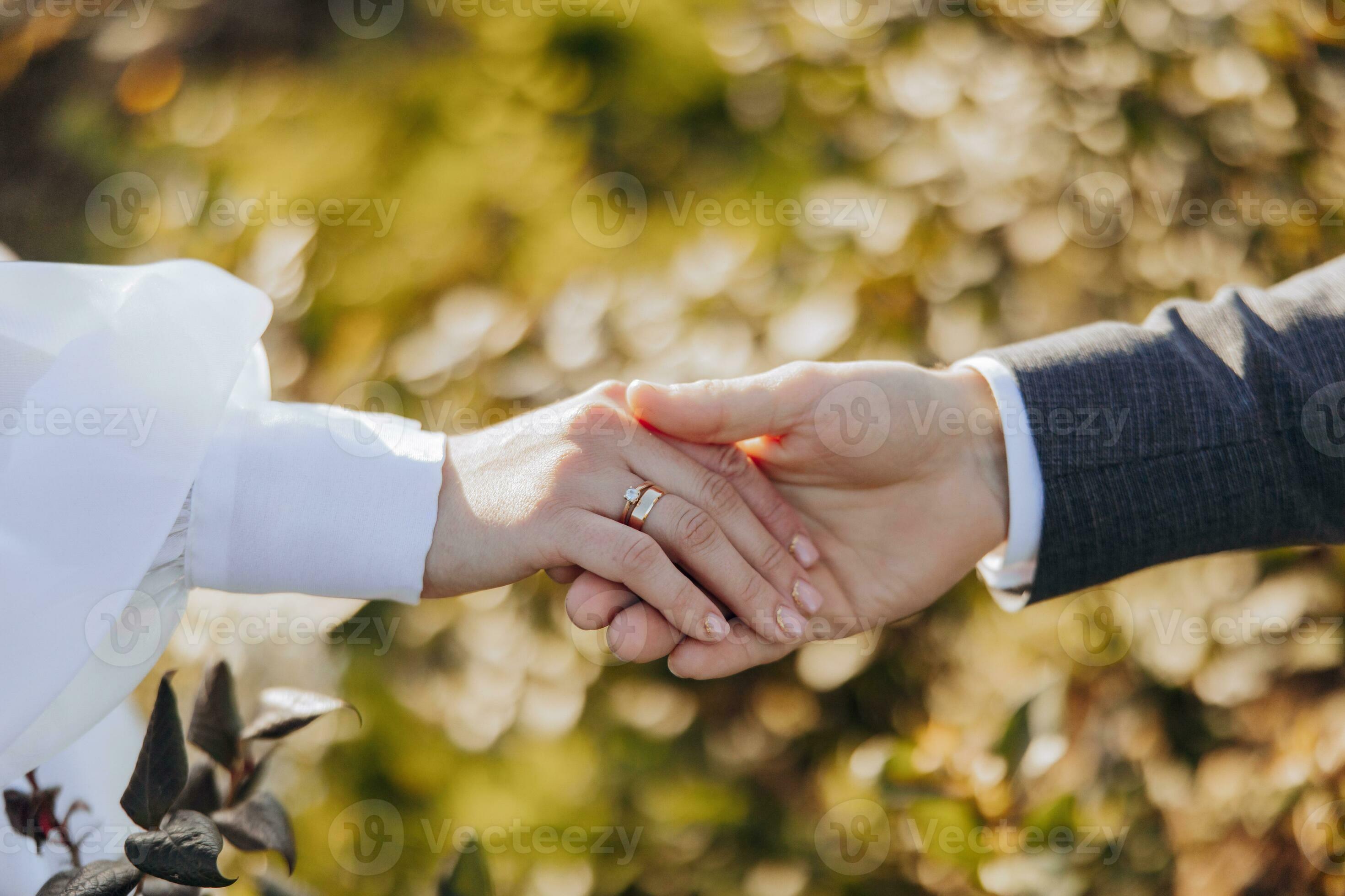 Close up shot of a bride and grooms hands interlocked showing a diamond ...
