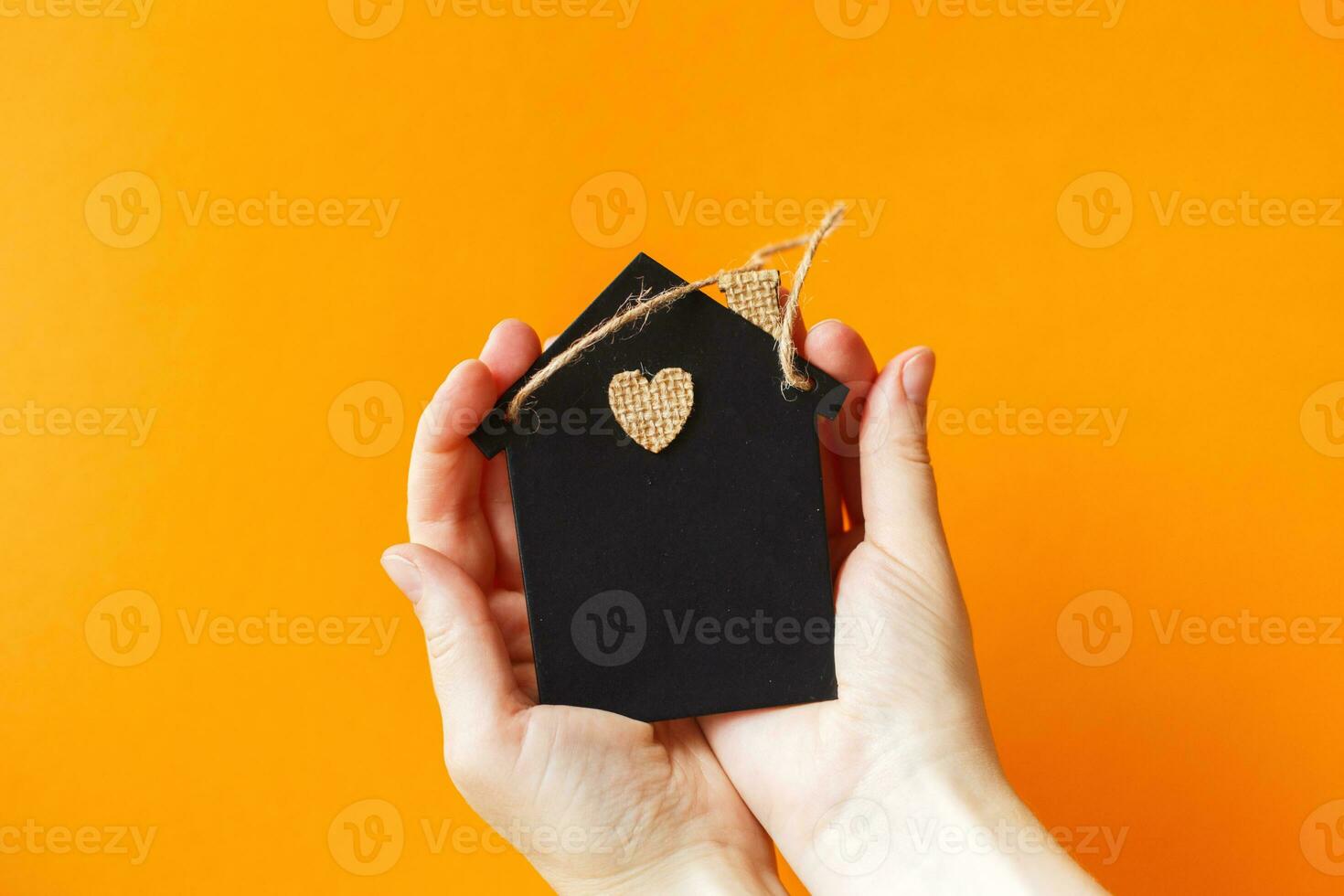 Womans Hand Holding Little Toy House On An Orange Background Home Insurance Concept 25399847