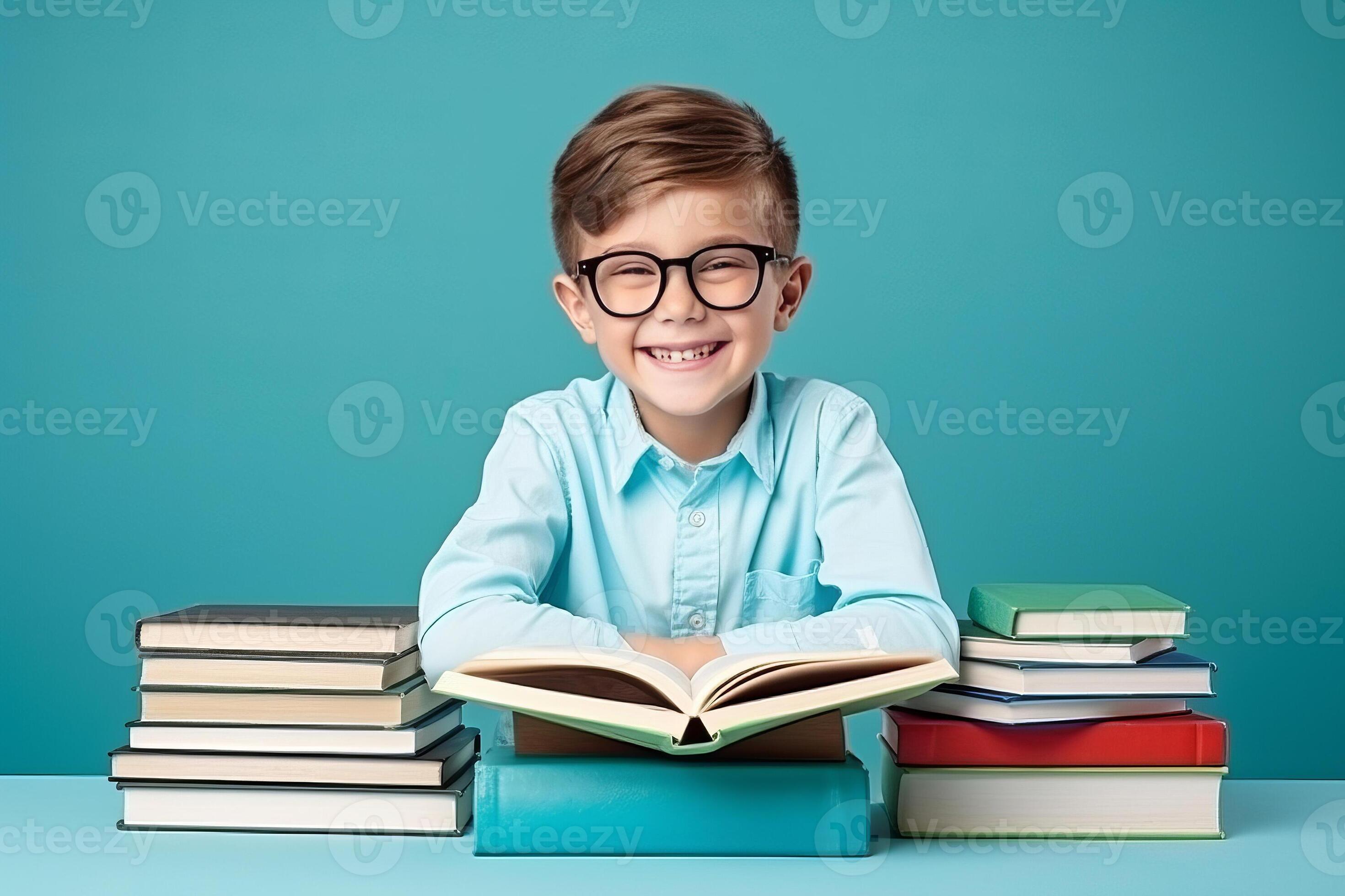 portrait of a happy child little boy with glasses sitting on a stack of ...