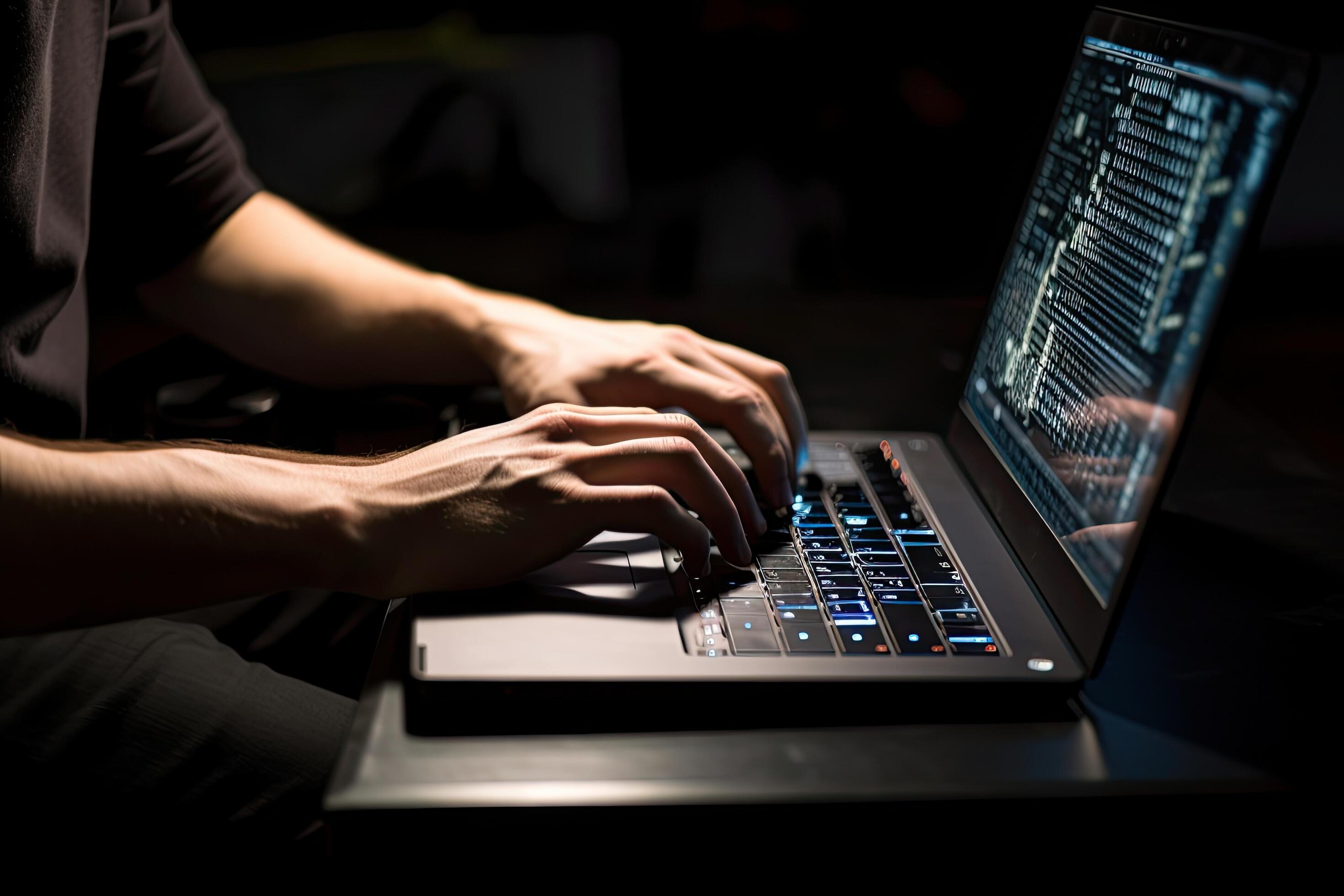 Man working on laptop computer in dark room. Close up of male hands typing on keyboard, A ...