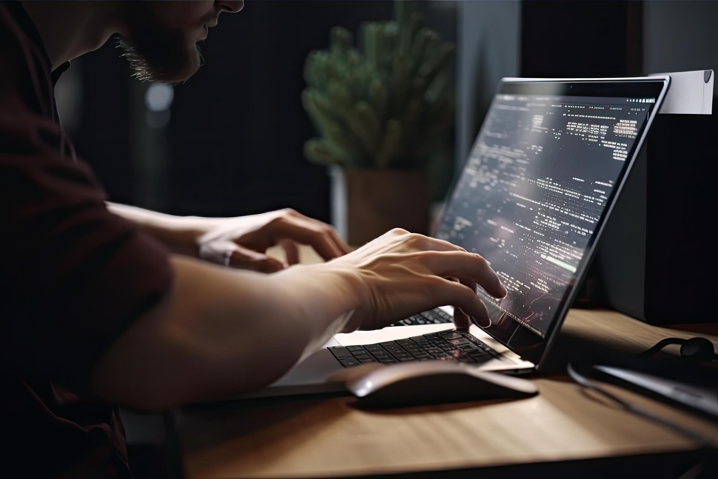 Programmer working on laptop in dark office. Programmer typing code on computer. Male programmer ...