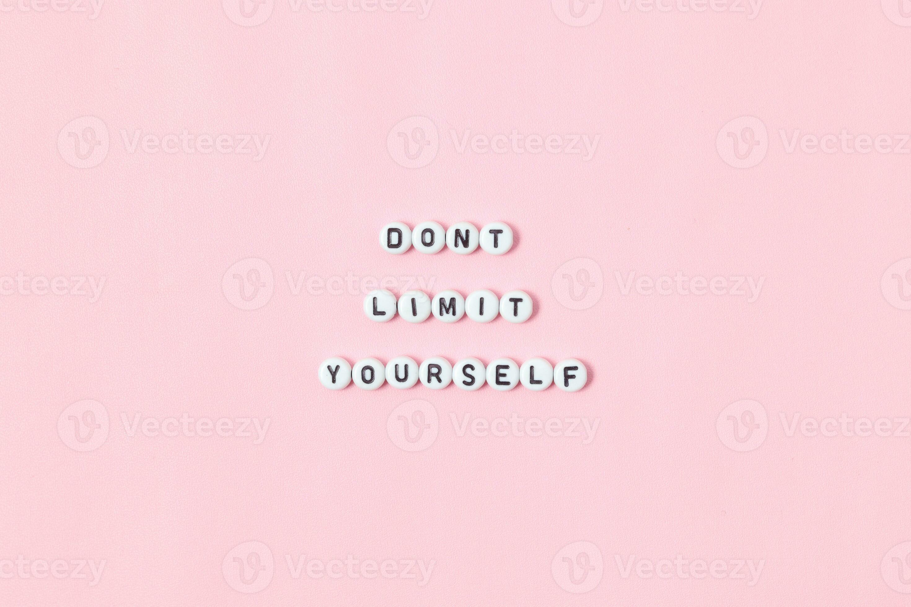Top View Of Dont Limit Yourself Quotes Made Out Of Beads On Pink