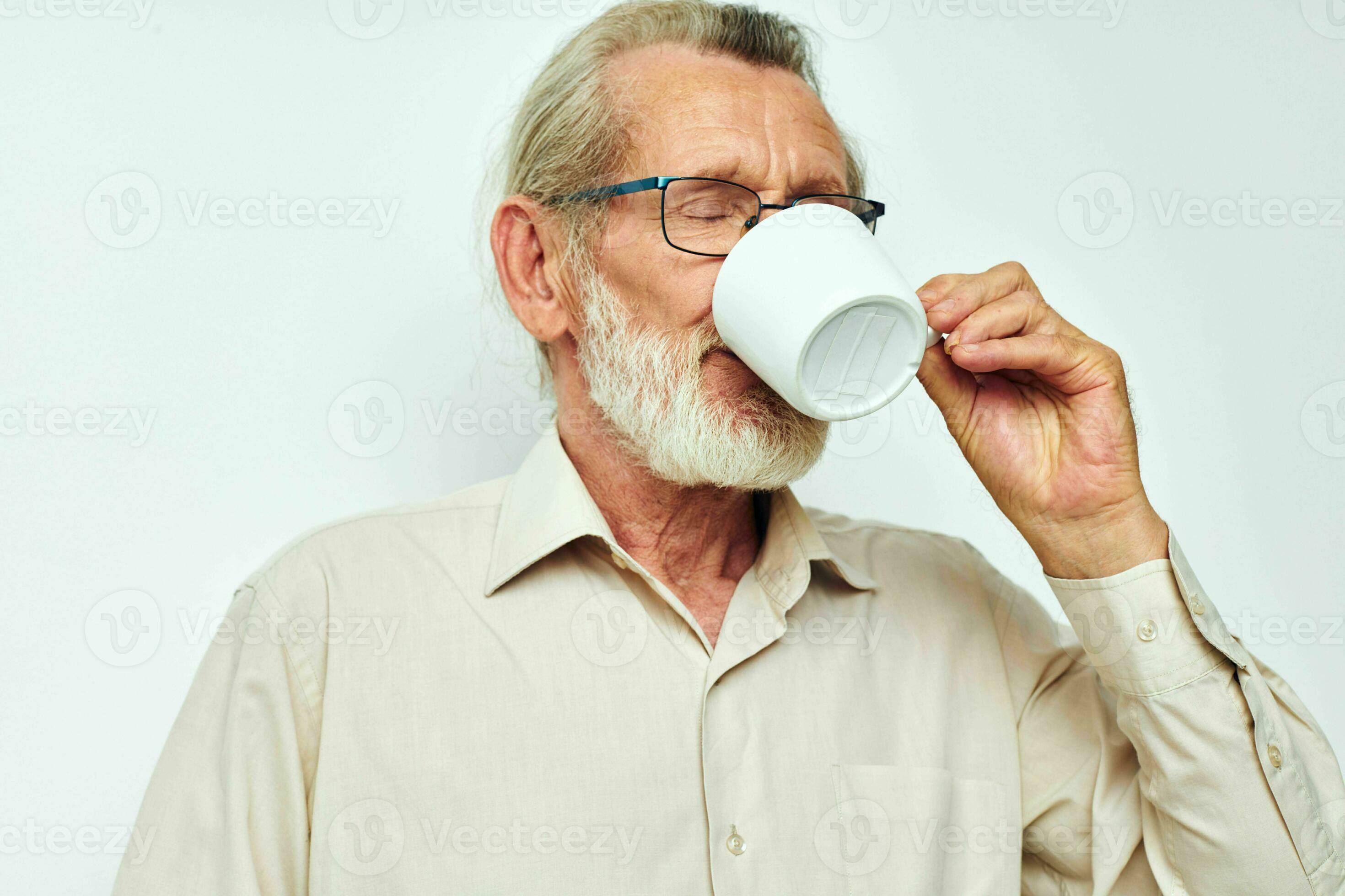 Elderly Man Drinking From A Mug On A White Background And Smiling