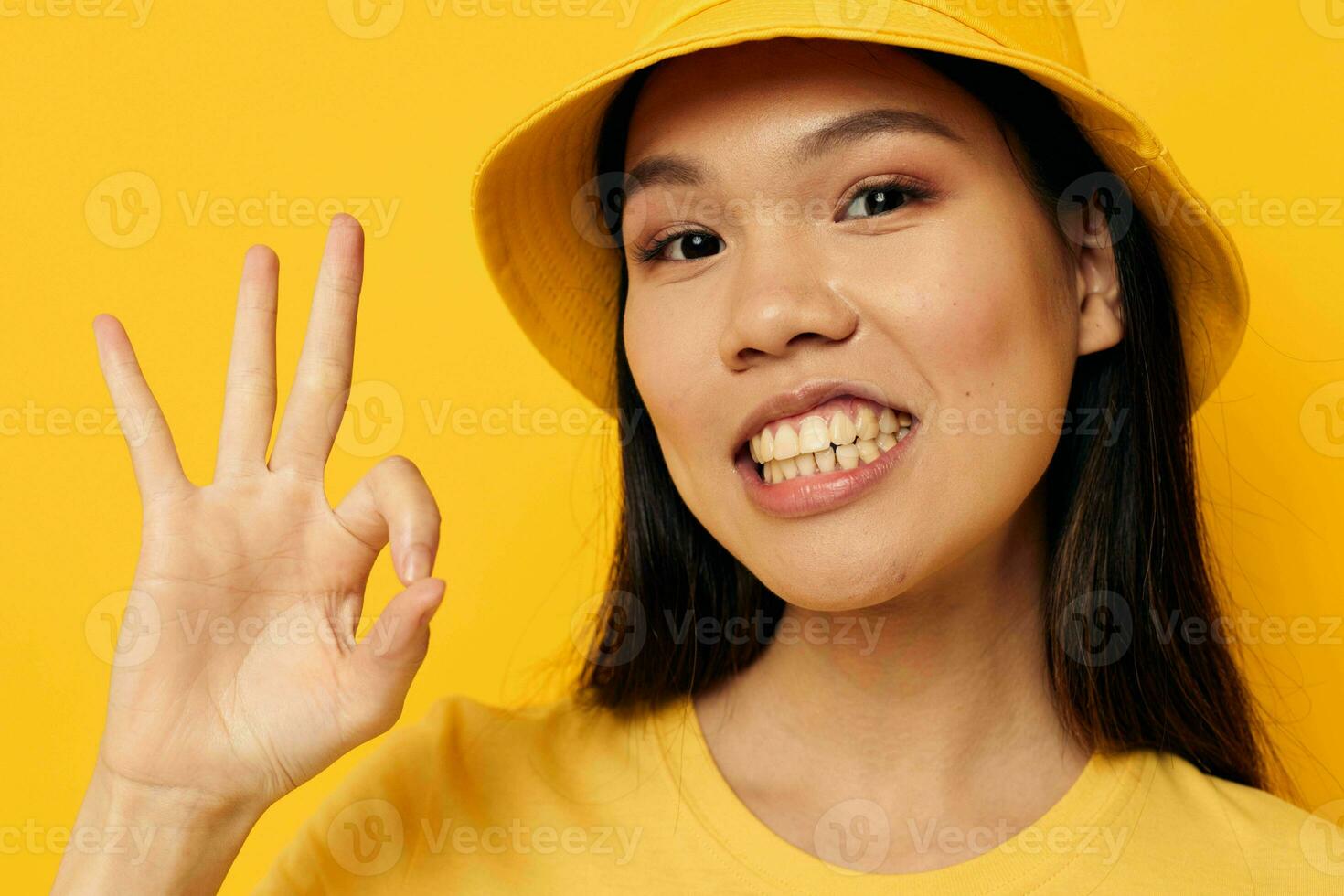 Woman With Asian Appearance In A Yellow T Shirt And Hat Posing Emotions