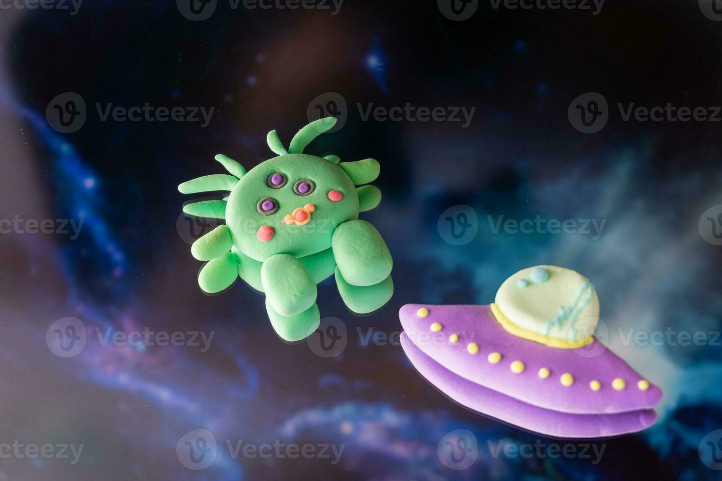 Alien spaceship UFO is flying at night. Clay hand made colorfull figures. Childrens fantasy ...