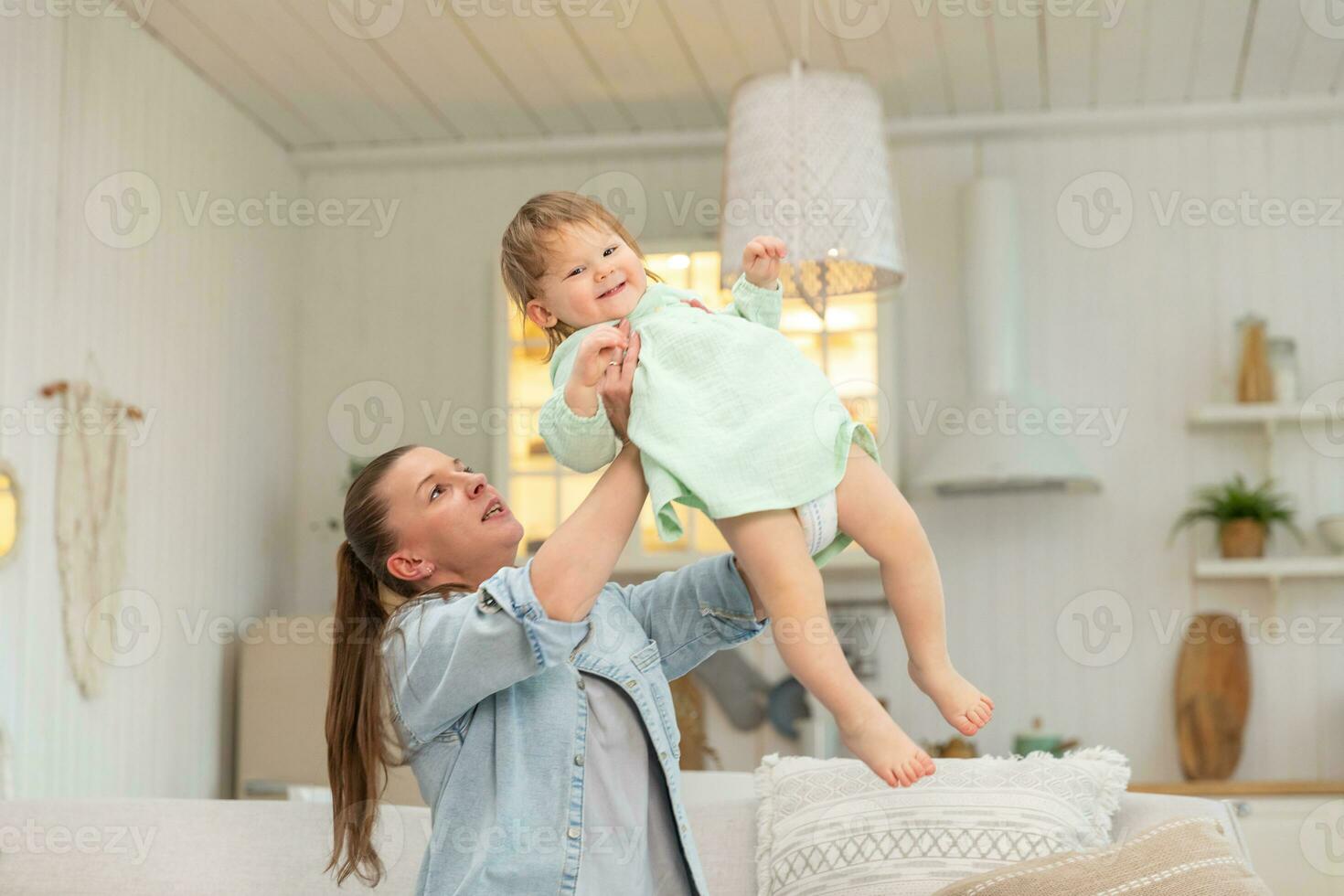Happy family at home. Mother lifting in air little toddler child daughter. Mom and baby girl ...