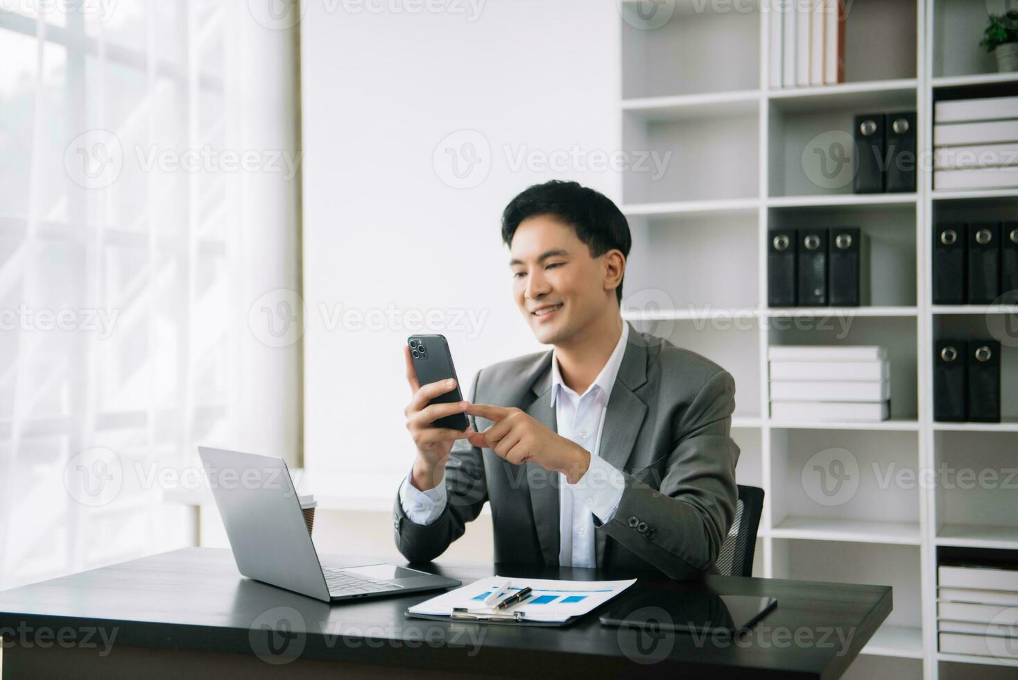 Young Asian business man using laptop and tablet while sitting at her ...