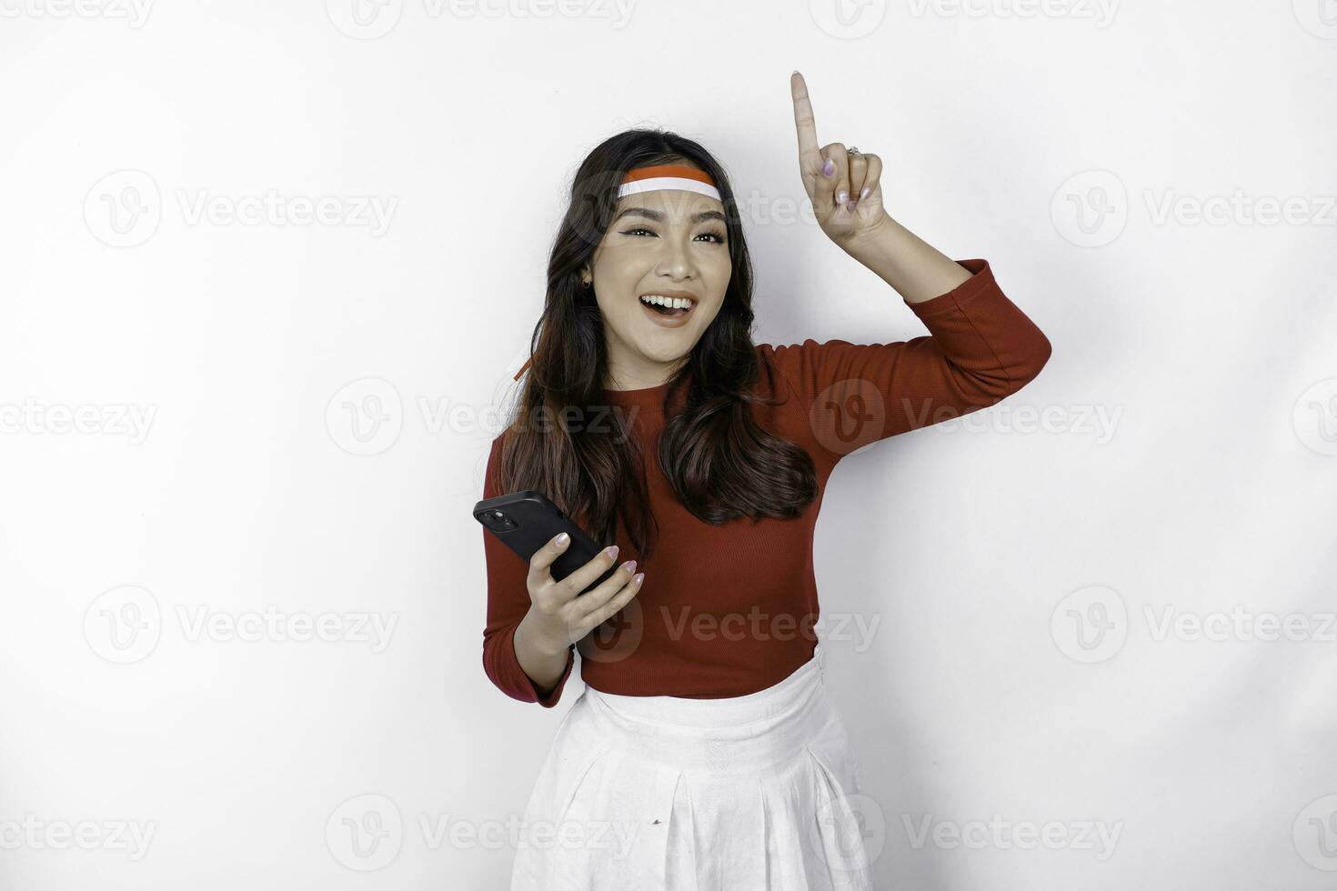 A Happy Asian Woman Wearing Headband Holding Her Phone And Pointing