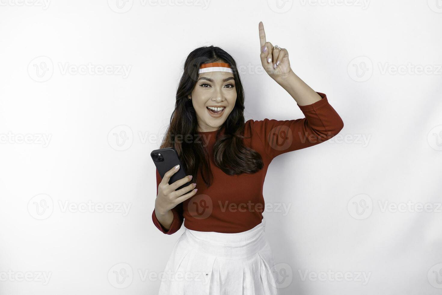 A Happy Asian Woman Wearing Headband Holding Her Phone And Pointing