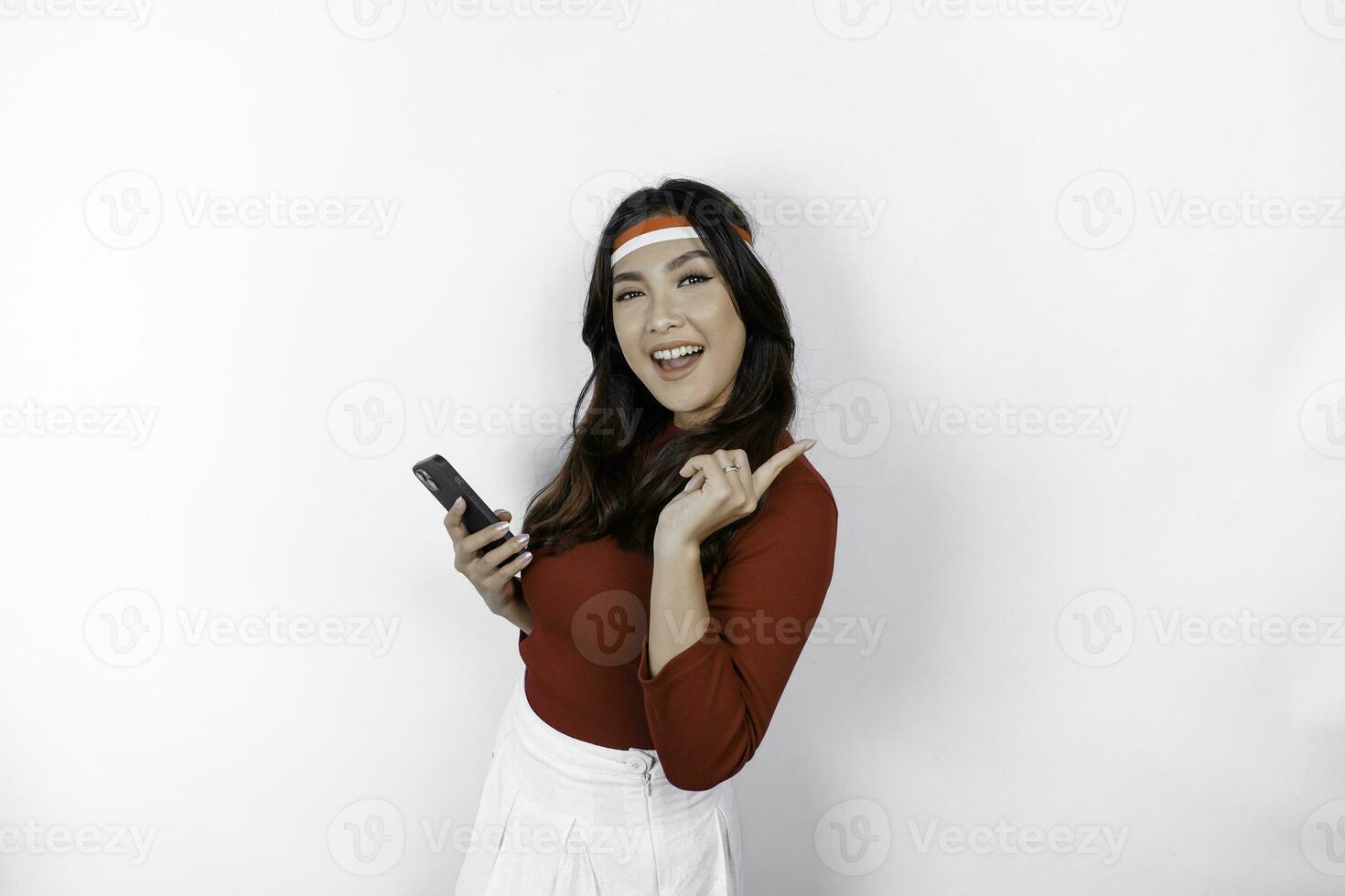 A Happy Asian Woman Wearing Headband Holding Her Phone And Pointing