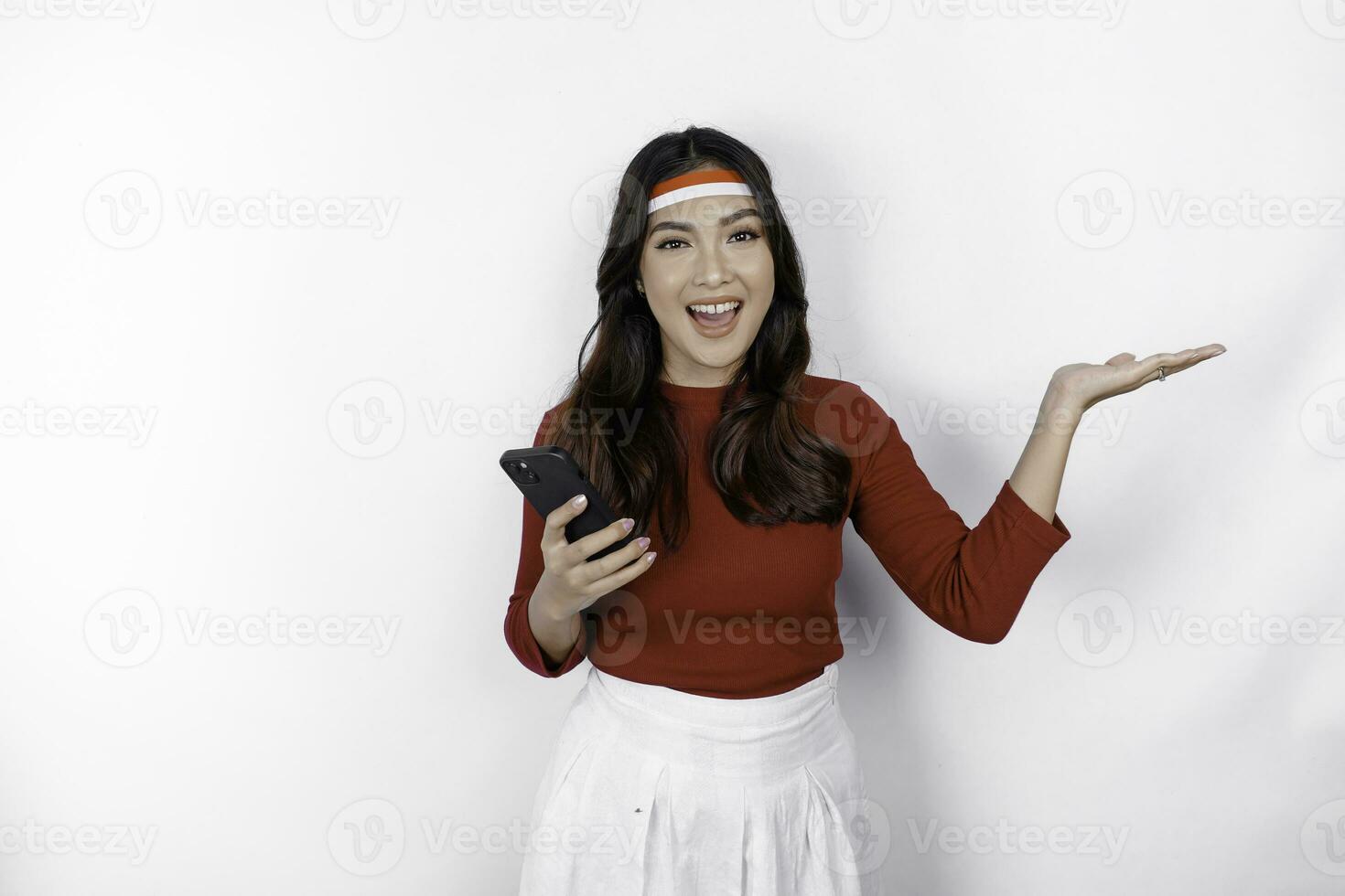 A Happy Asian Woman Wearing Headband Holding Her Phone And Pointing