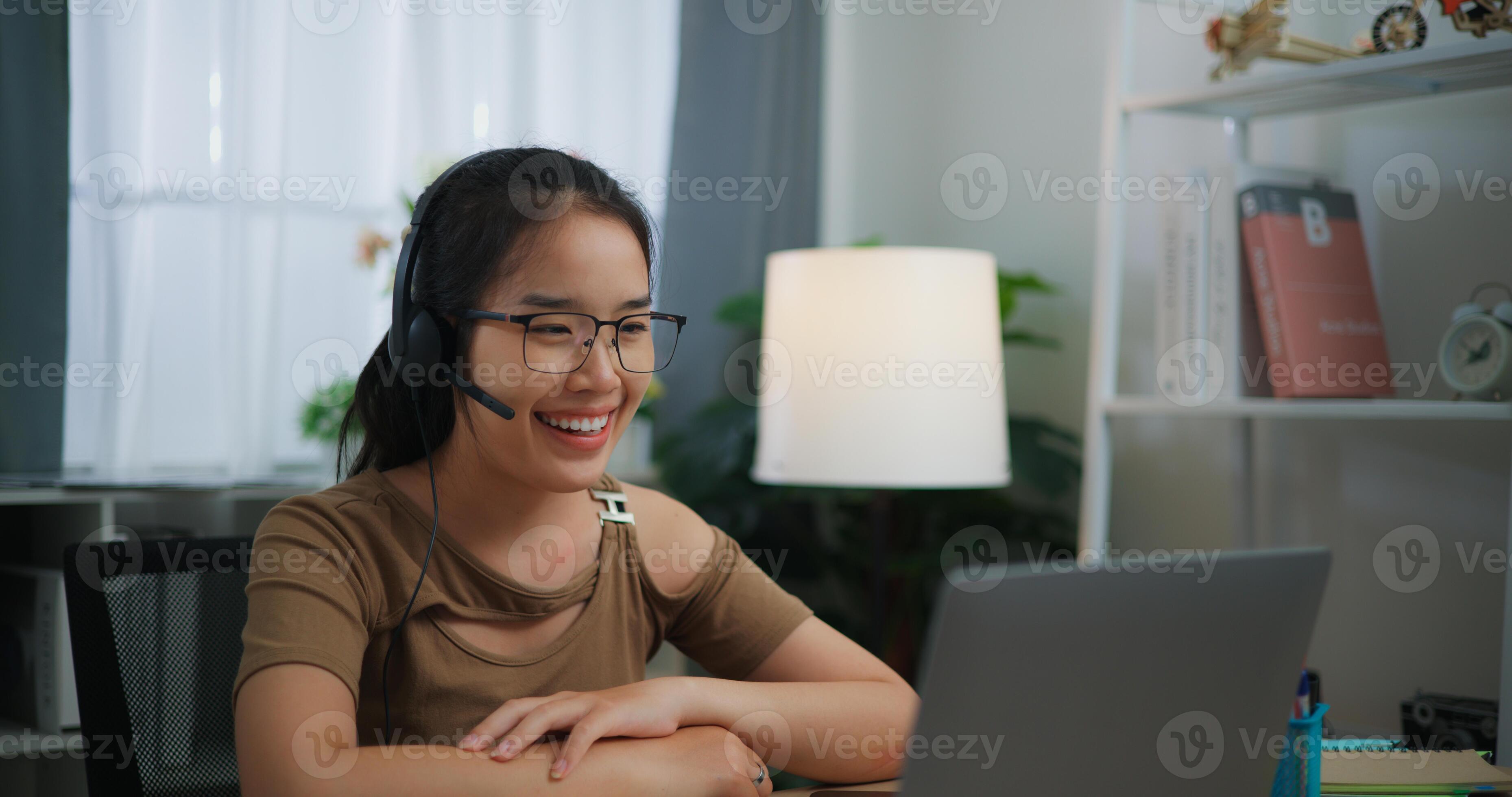 Young Asian woman wearing glasses using a laptop on a desk 26306904 ...
