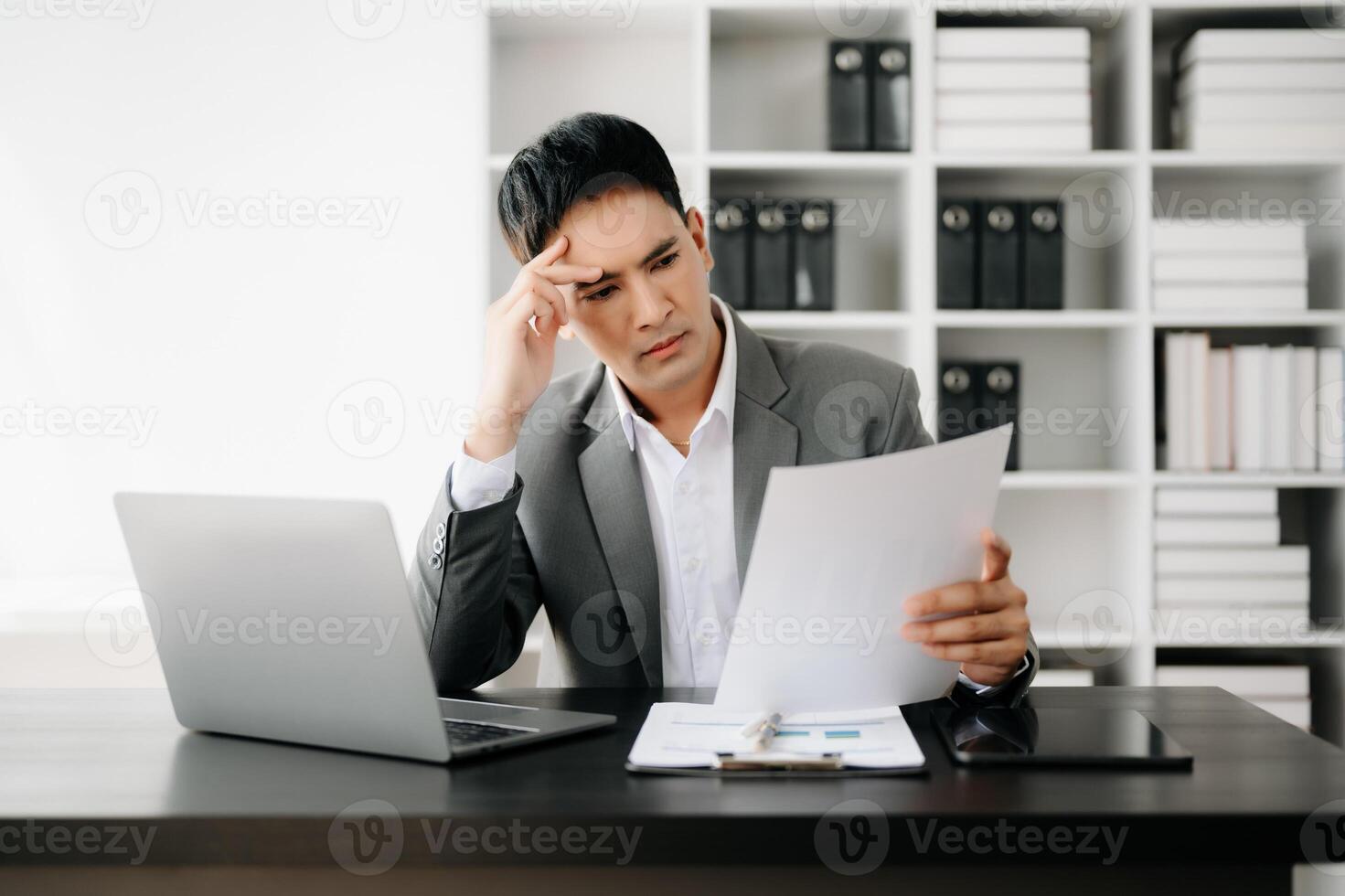 Frustrated young businessman working on a laptop computer sitting at ...