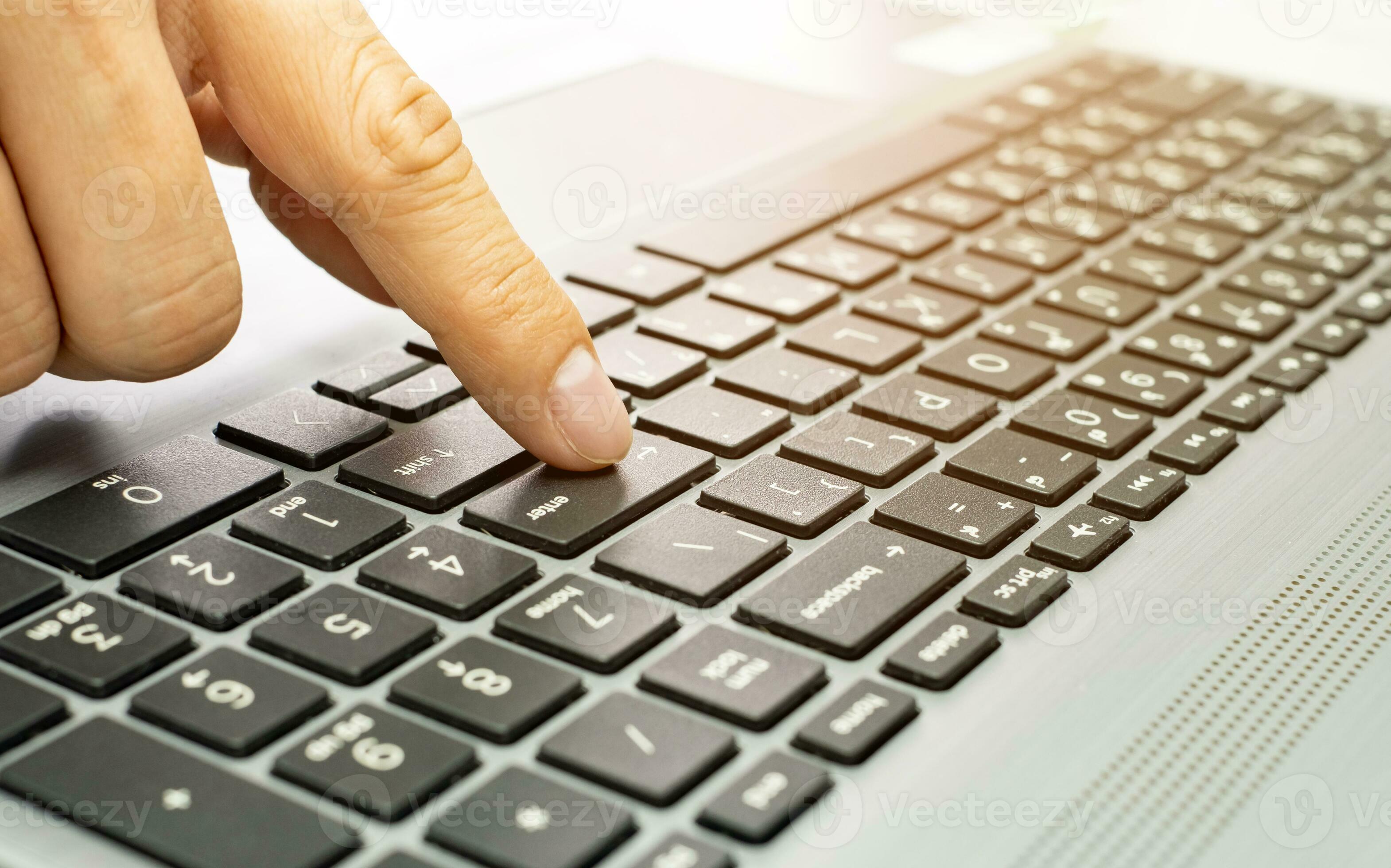 Close up of Human finger pressing enter key on laptop keyboard confirming computer system ...