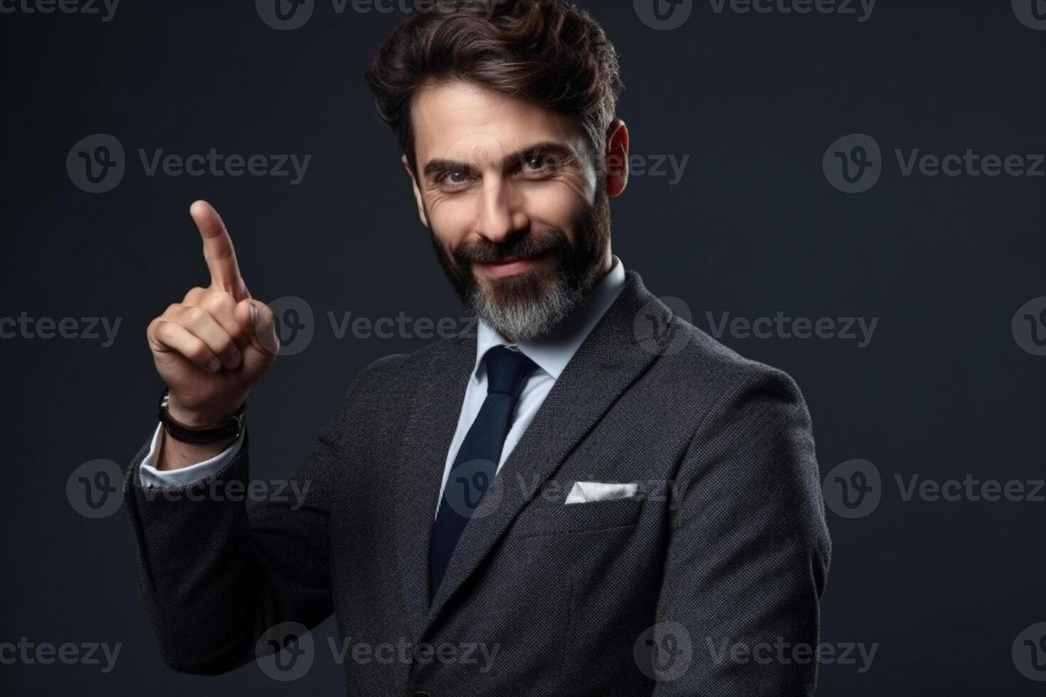 Cheerful young man in suit pointing at camera with index finger ...