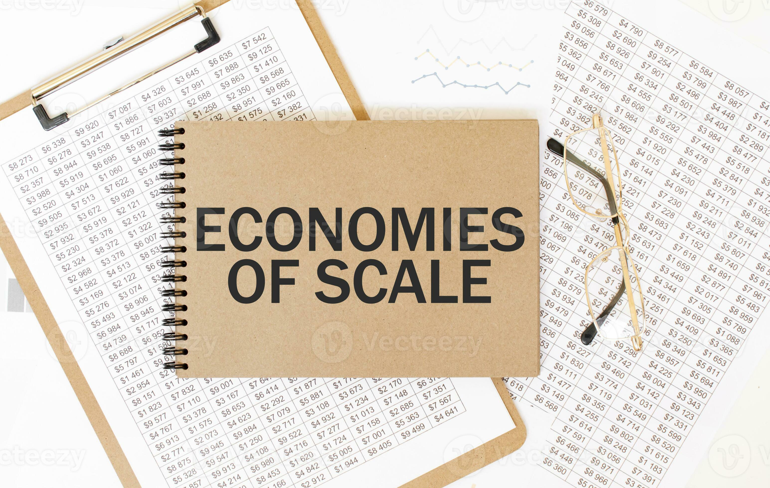 Craft colour notepad with text ECONOMIES OF SCALE. Notepad with eyeglasses and text documents ...