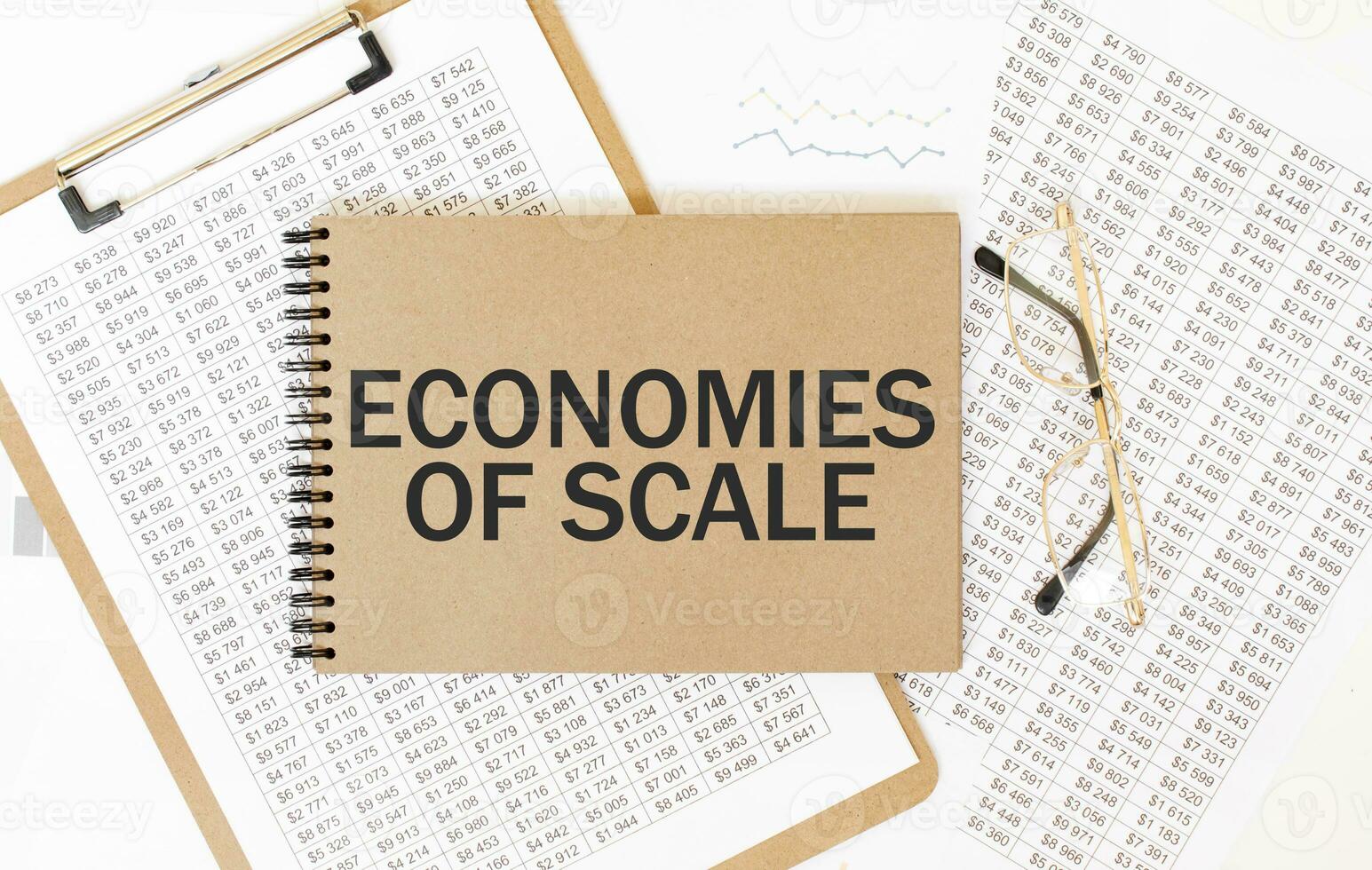 Craft colour notepad with text ECONOMIES OF SCALE. Notepad with eyeglasses and text documents ...