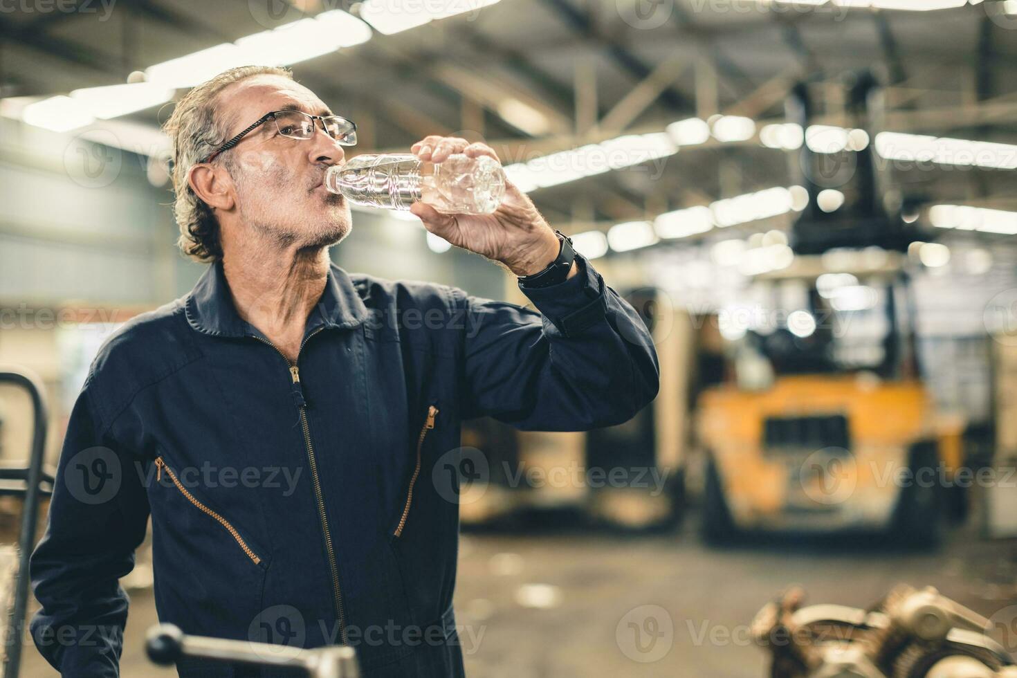 Thirsty senior male staff worker drinking water refreshing from tired hard work in hot workplace ...