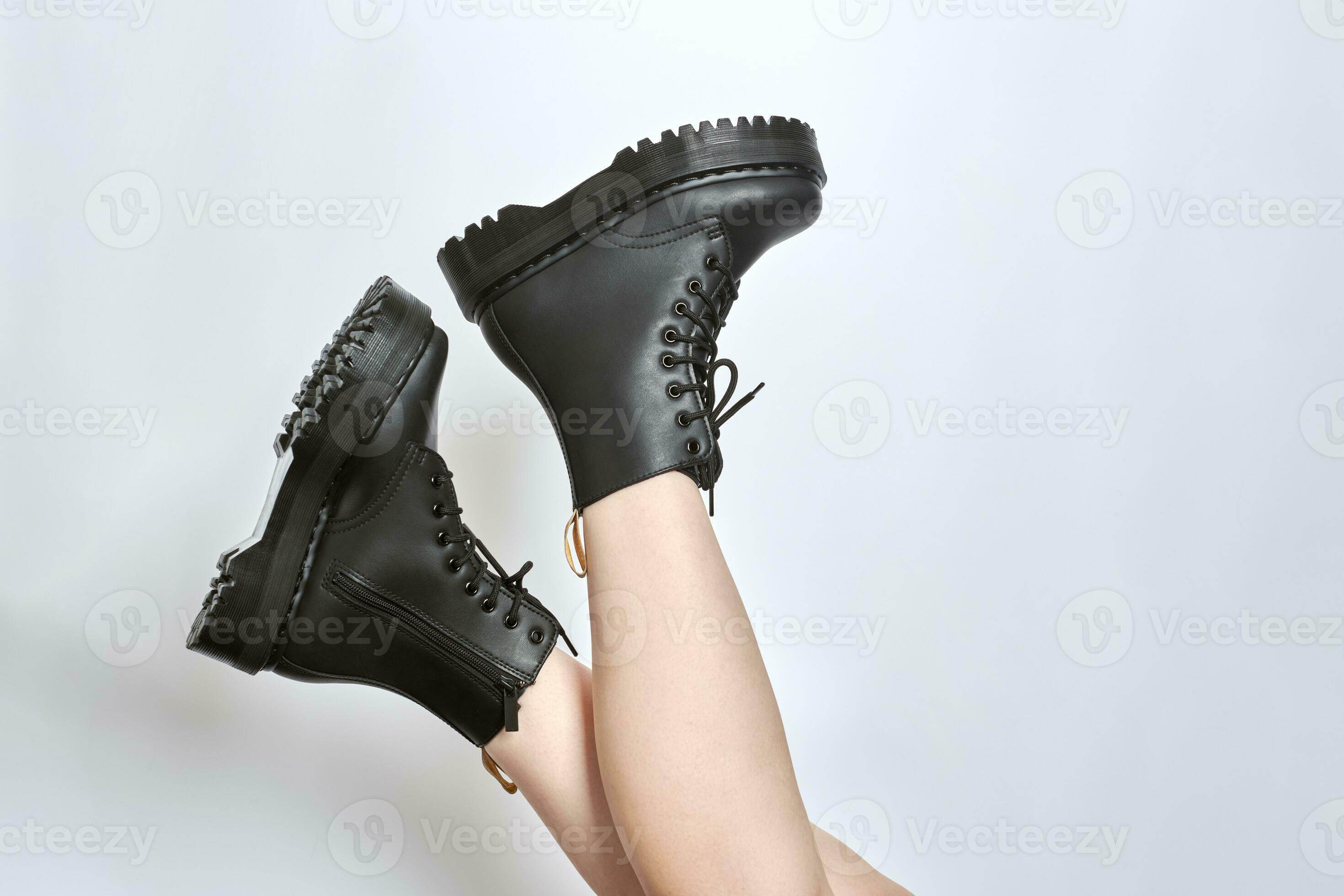 Woman legs in black combat boots on high heel platform with lug soles upside down, white ...