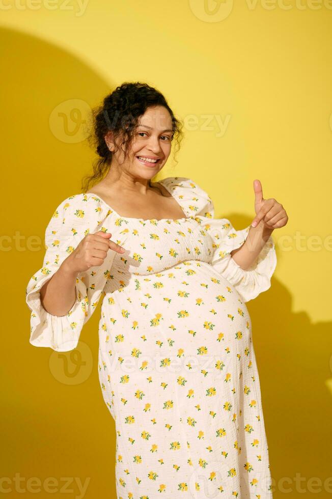 Multi Ethnic Pregnant Woman In Sundress Points Her Fingers At Her Big