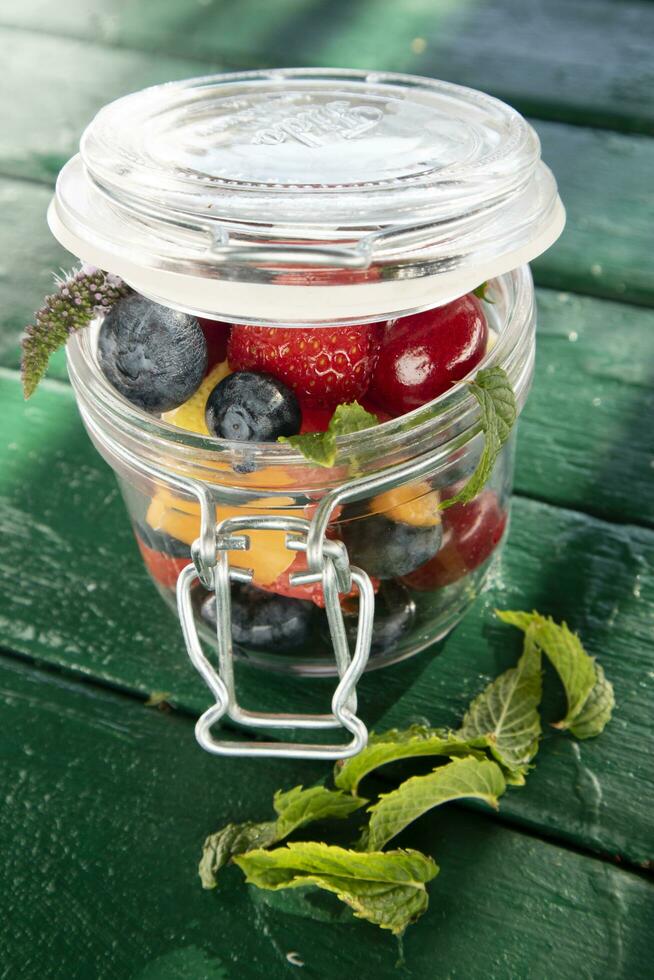 Colorful Mixed Fruit Salad In Glass Container In Green Background