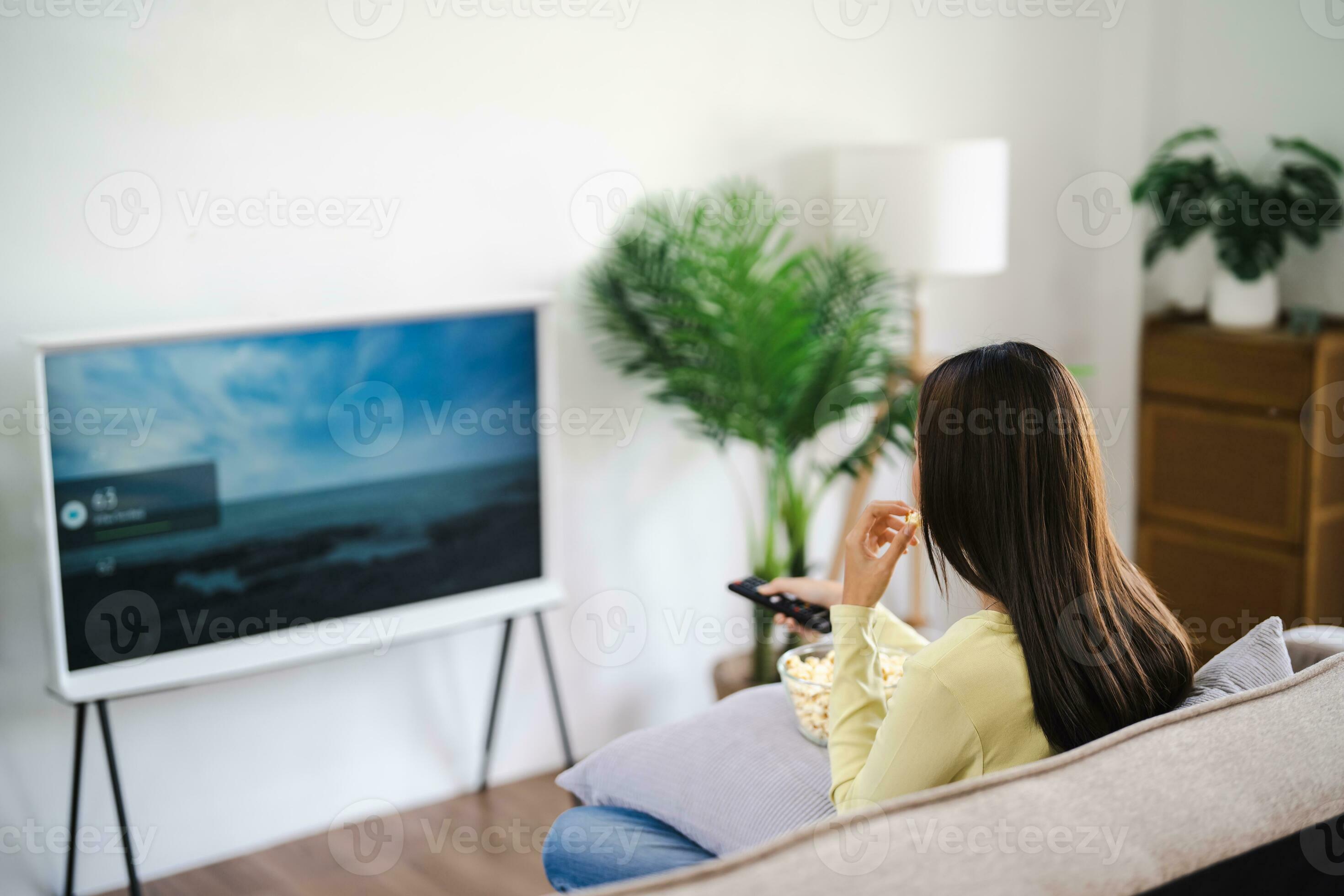 Asian woman Watching smart TV and using remote controller Hand holding television audio remote ...
