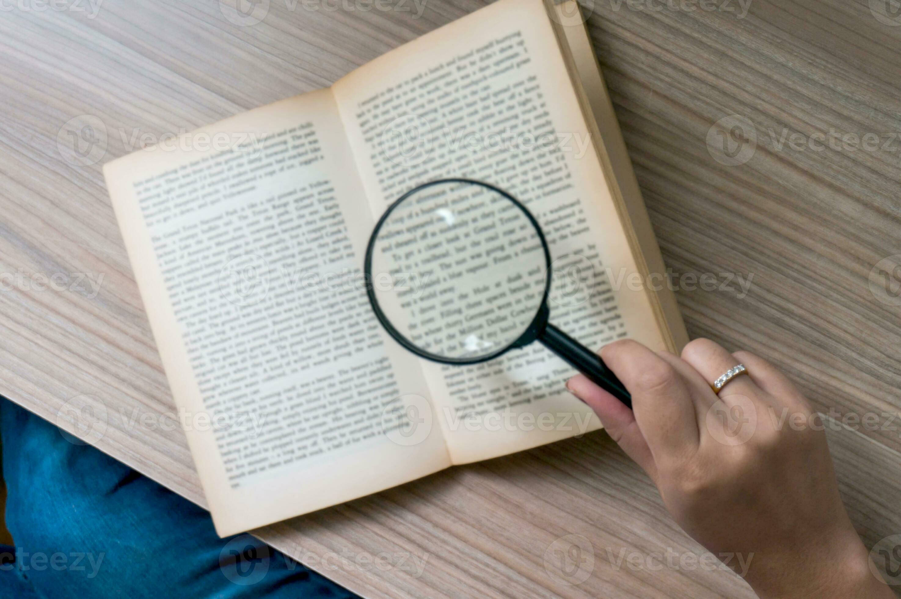 Books and a magnifier Research concept. Magnification glass over a ...