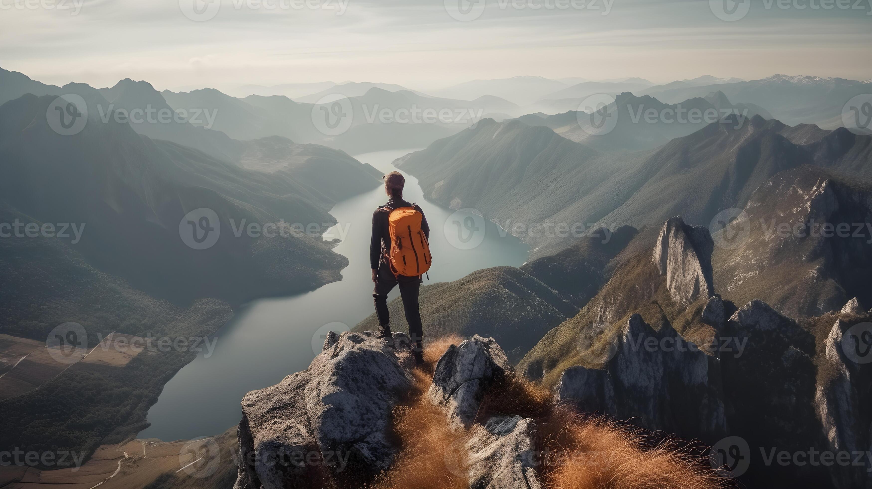 An adventure man or a hiker standing at the edge cliff in a high mountain peak watching the ...