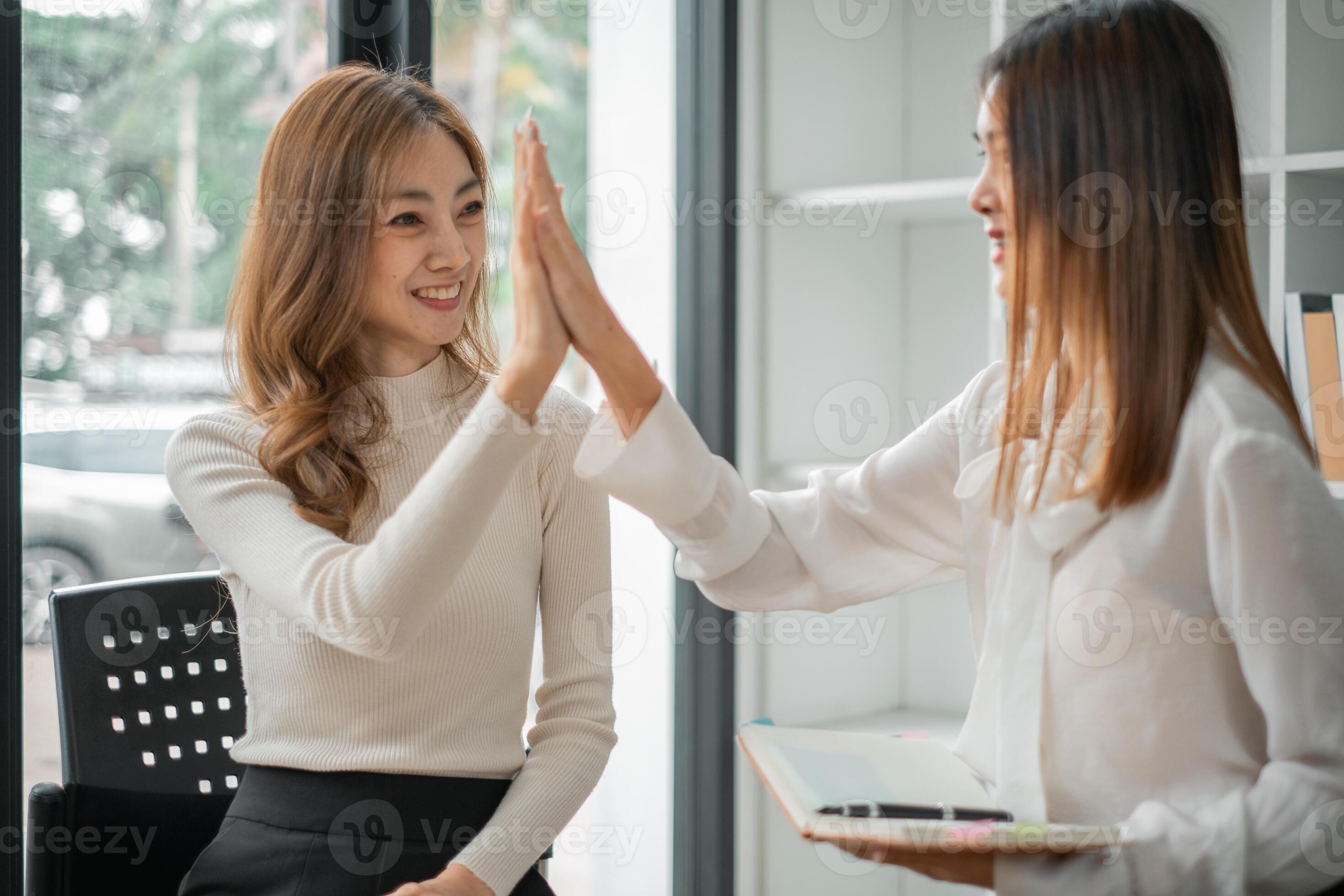 Businesswoman Giving A High Five To Female Colleague In Meeting