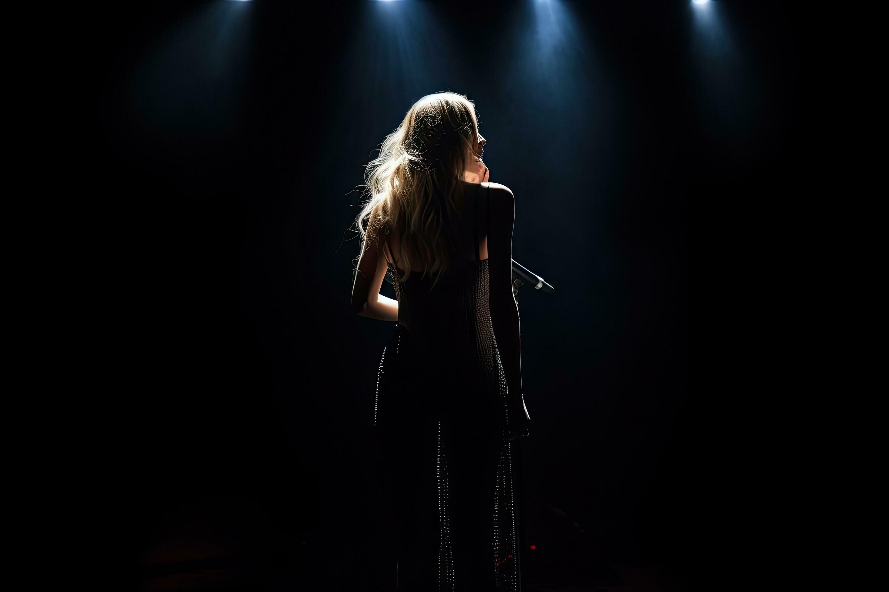 Beautiful woman singing into microphone on stage in a dark room ...