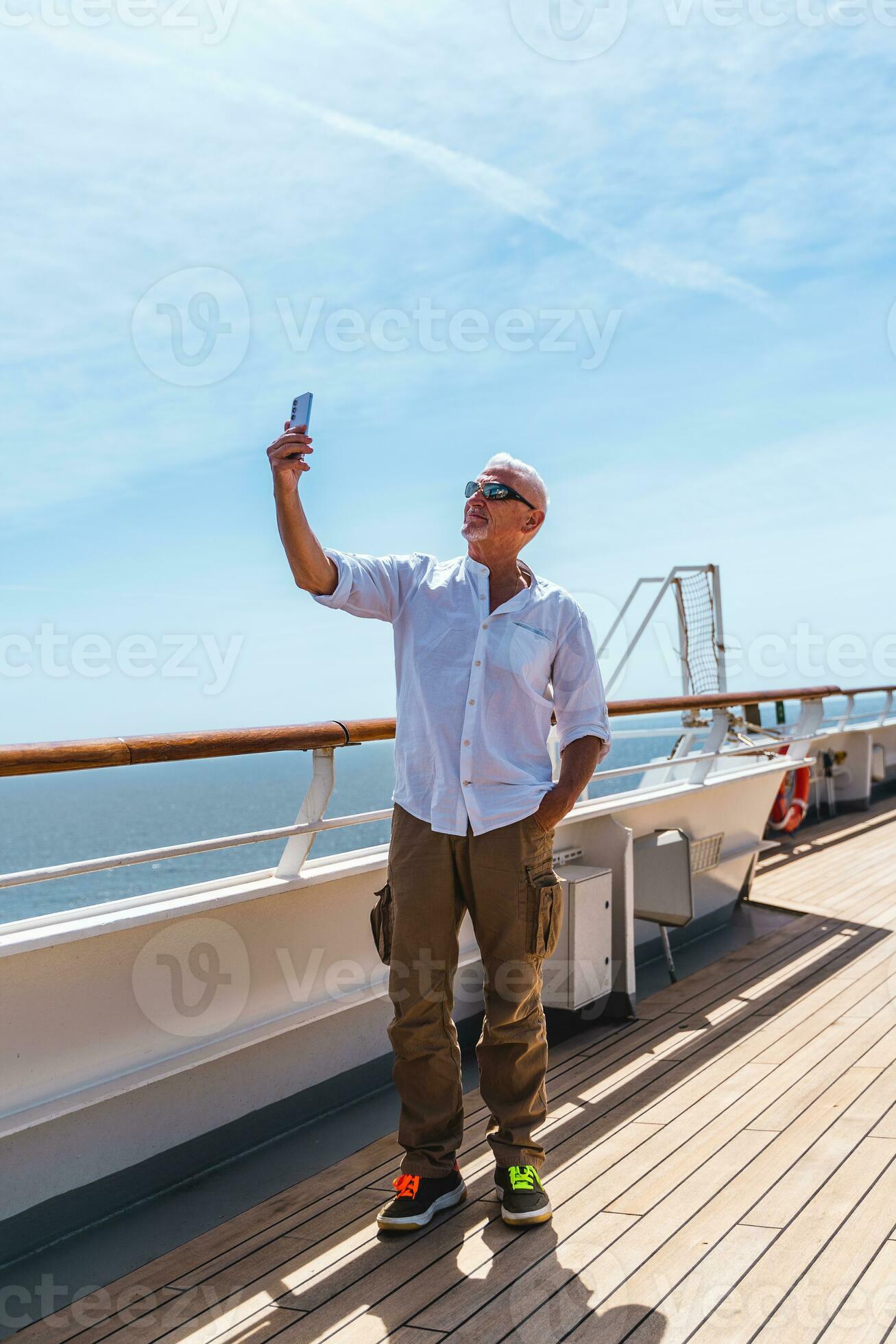 happy handsome middle aged man taking a selfie on the deck of a cruise ...