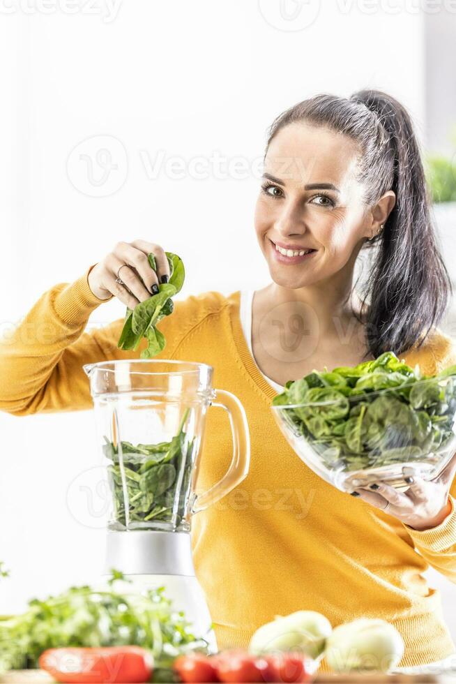 Smiling Woman Making Spinach Smoothie Putting Leaves In Blender